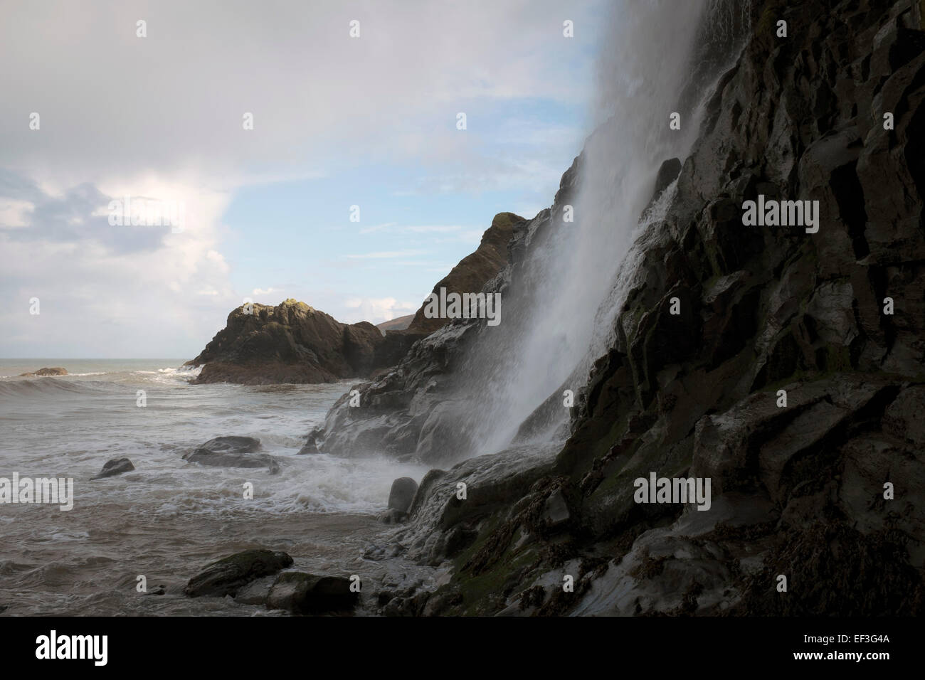 A waterfall cascading over rocks on to the beach in the village of ...