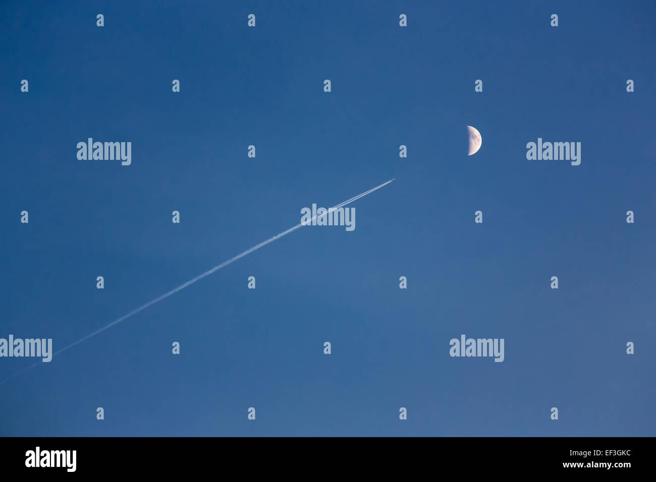 Trace of the jet plane in the blue sky with the moon on a background ...