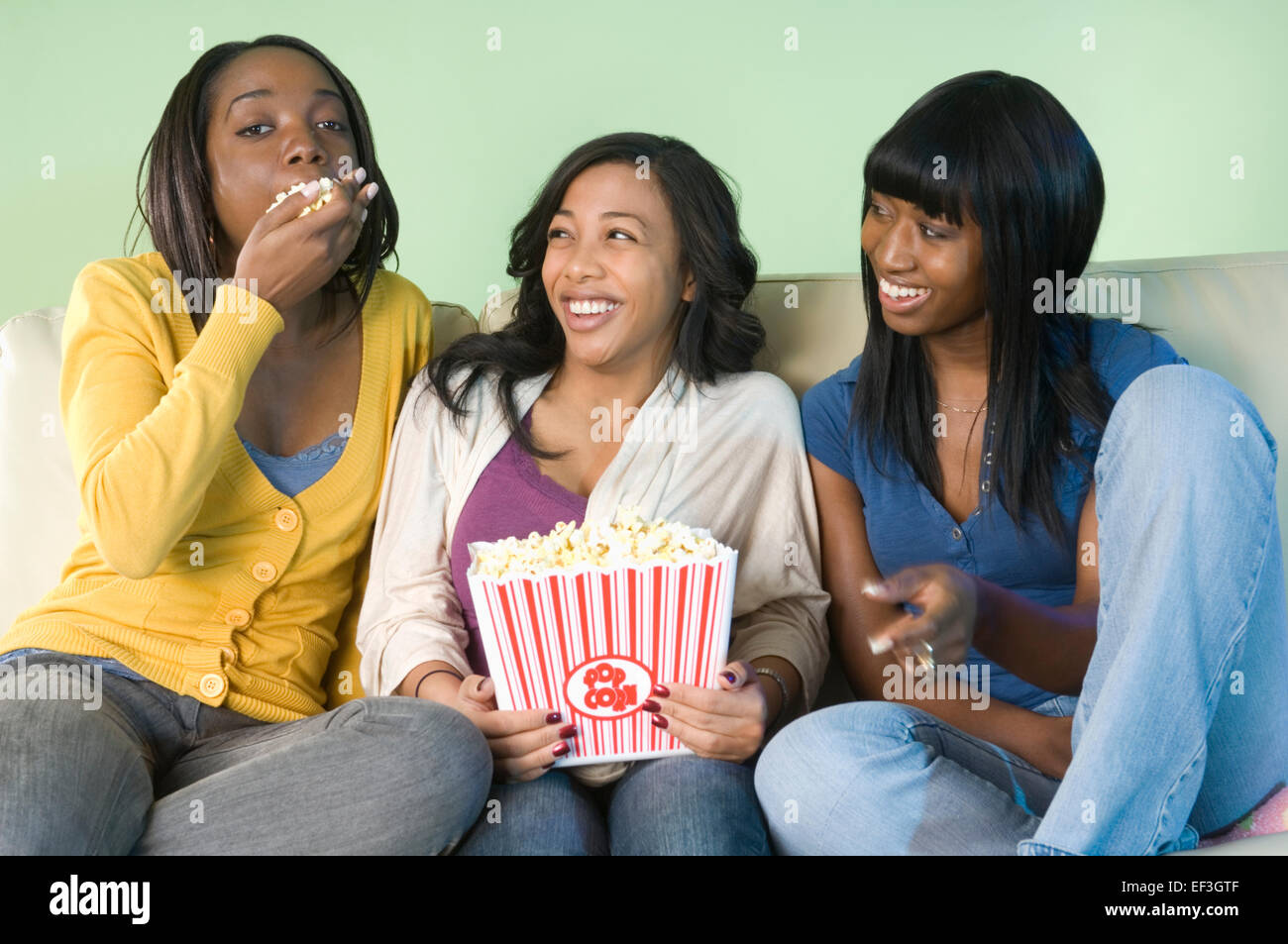 Three friends eating popcorn Stock Photo - Alamy