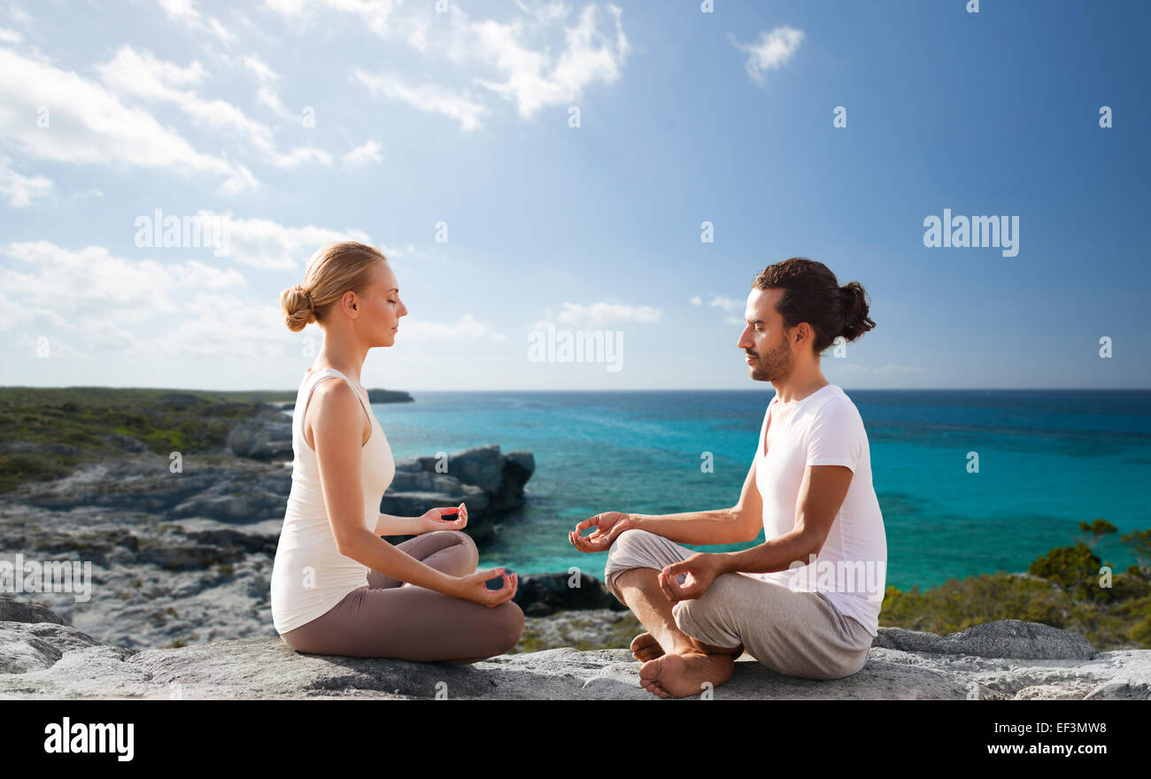 happy couple meditating in lotus pose on beach Stock Photo - Alamy