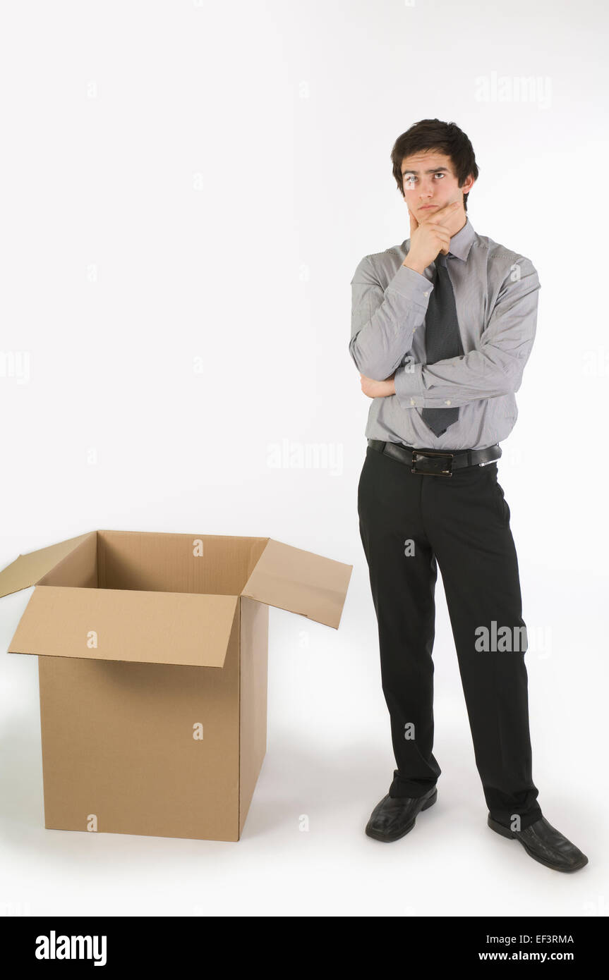 Contemplative businessman standing beside an empty box Stock Photo - Alamy