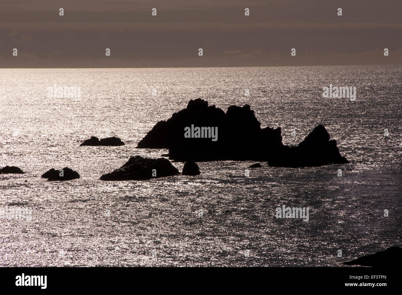 A silhouetted view of islands of the coast a the Lizard in Cornwall ...