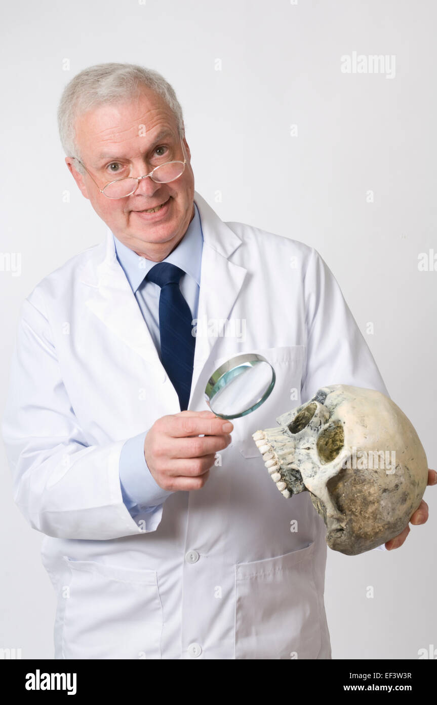 Doctor looking at skull with magnifying glass Stock Photo - Alamy