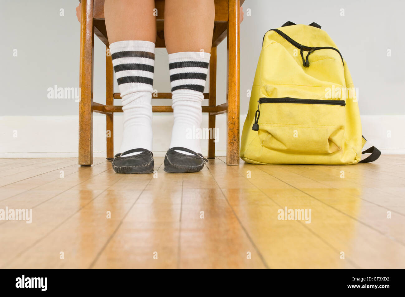 Girl's feet beside yellow backpack Stock Photo - Alamy