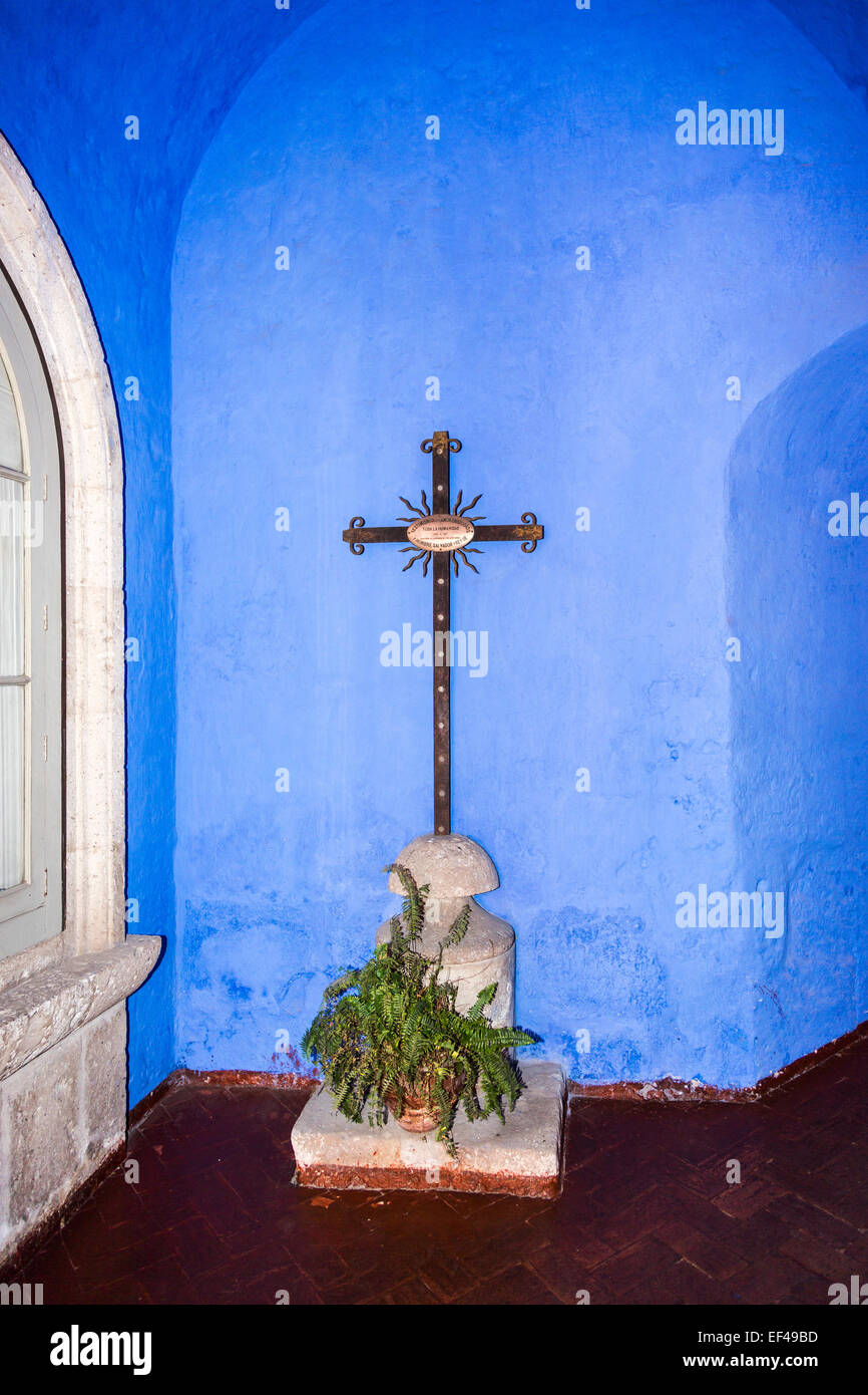 Vintage metal Christian cross standing against a bright blue wall ...