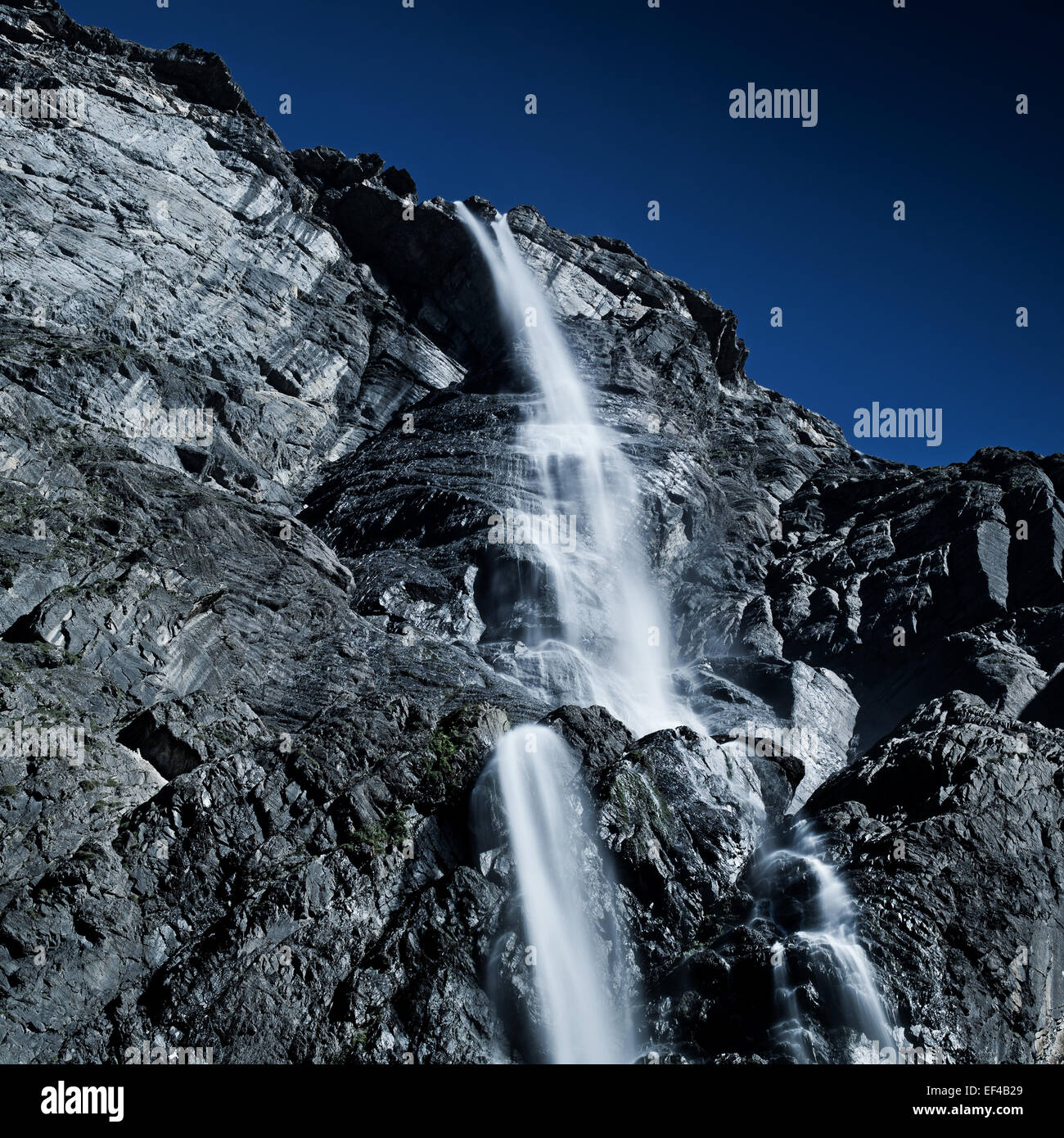 Waterfall in high mountains in Pyrenees. Dark contrast twilight colors ...