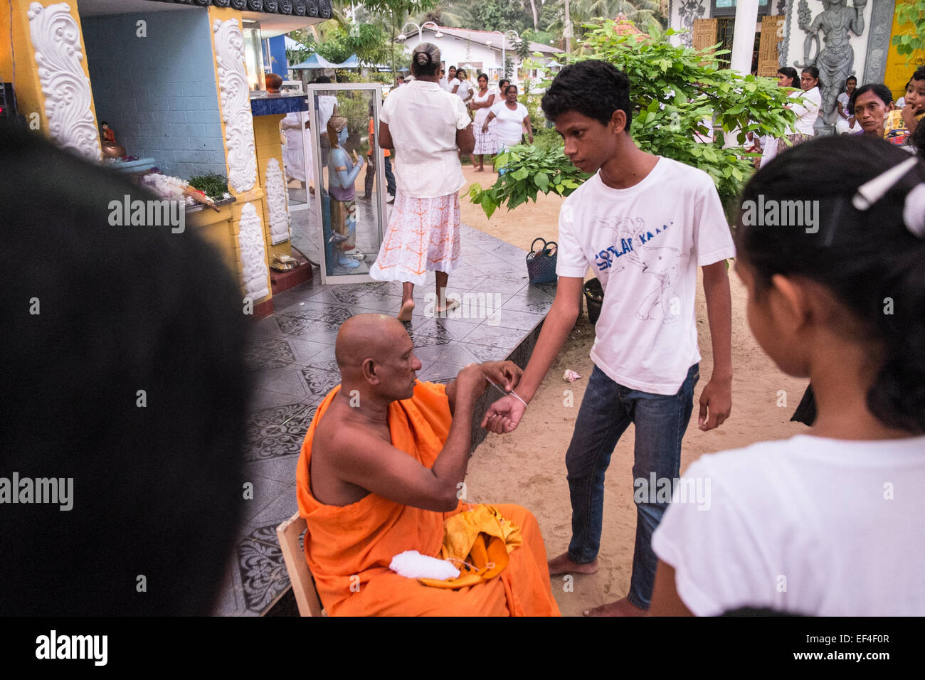 Buddhist monk tying sacred,holy blessed thread on to devotees wrists at ...