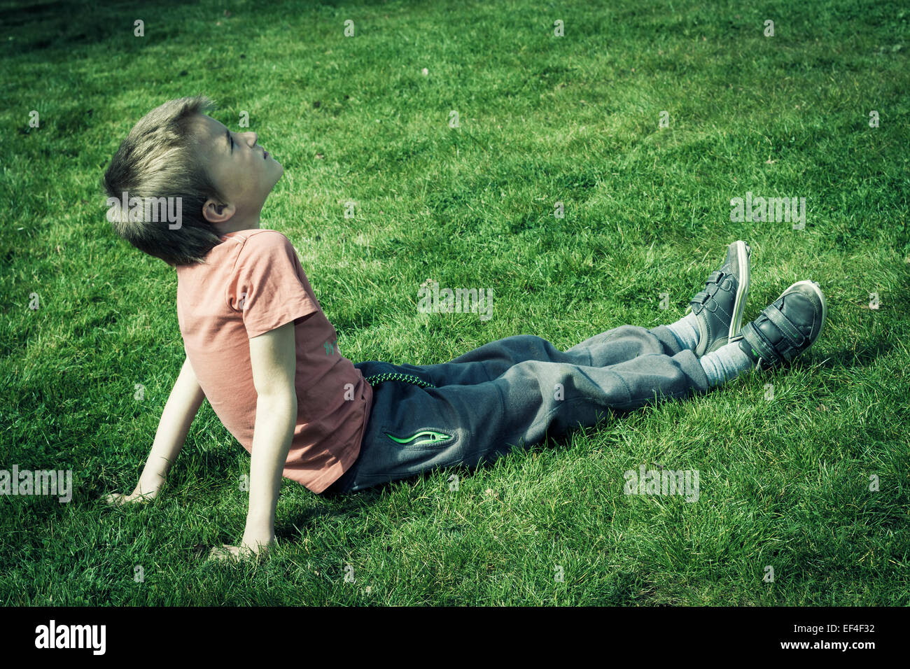 boy sitting grass looking up, 8 years old Stock Photo - Alamy