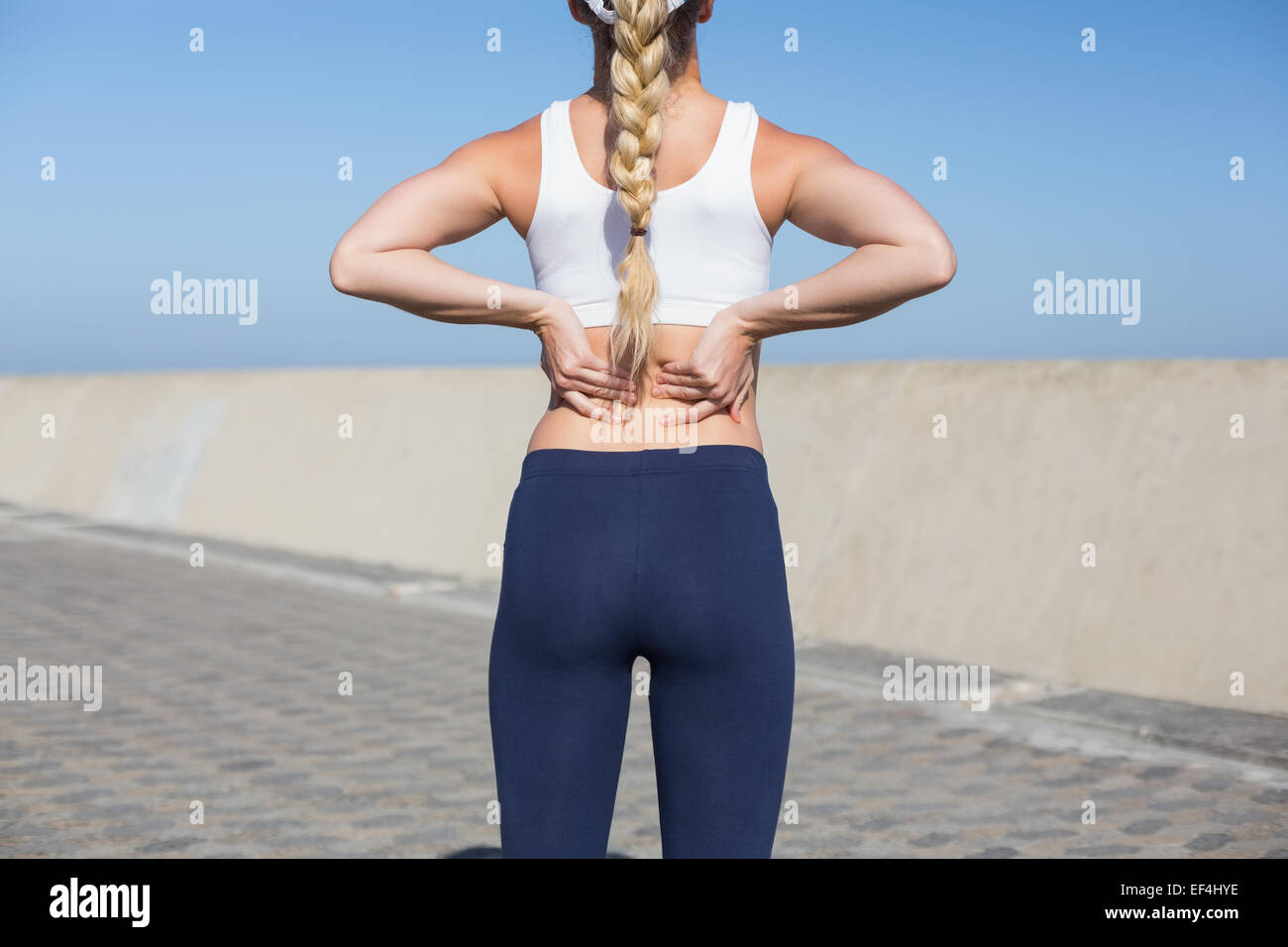 Fit blonde touching her back on the pier Stock Photo - Alamy
