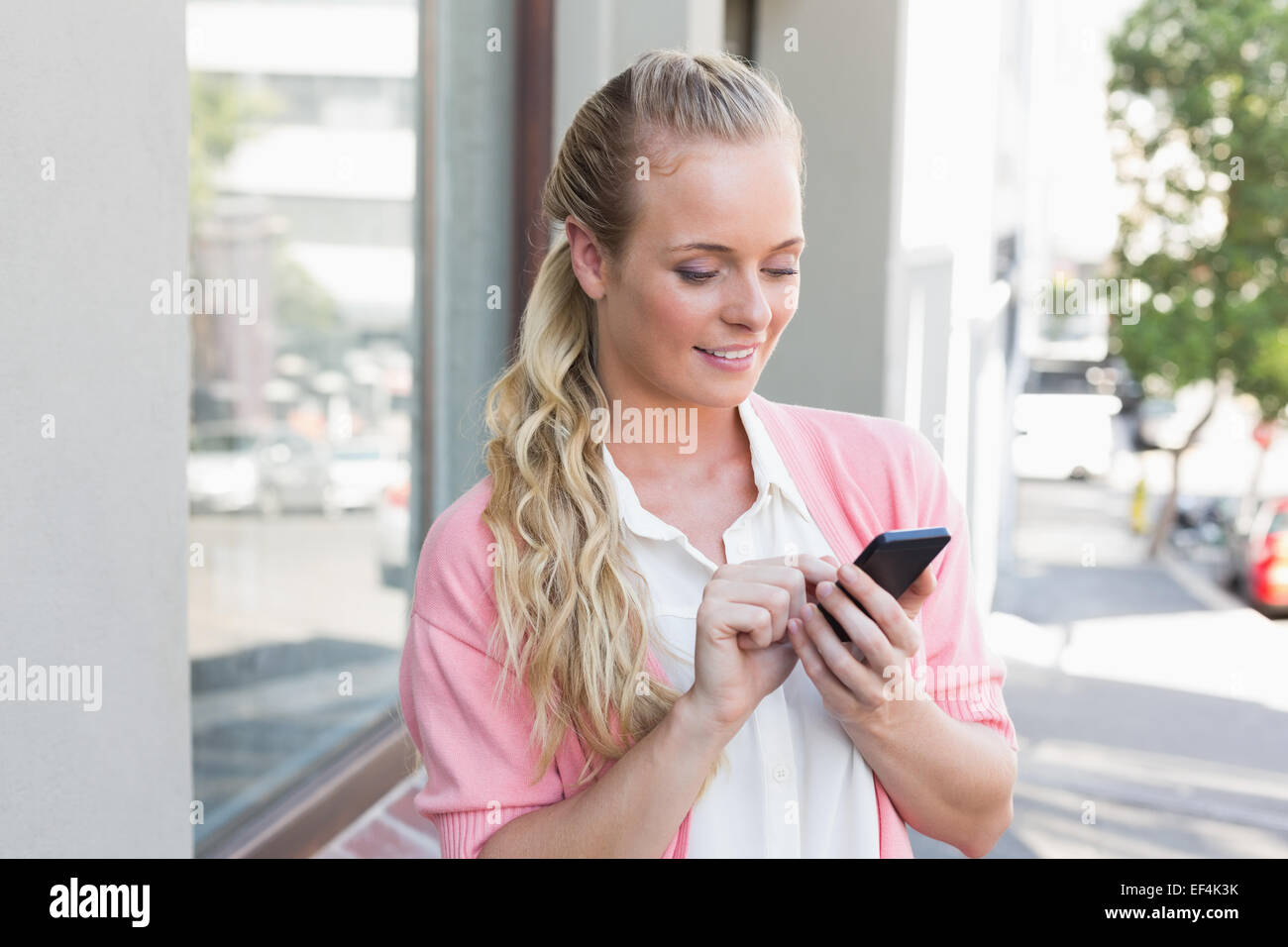 Pretty blonde sending a text message Stock Photo - Alamy