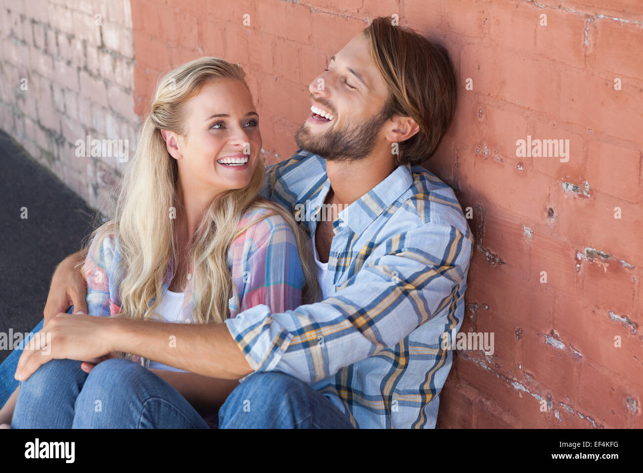 Cute couple sitting on ground Stock Photo - Alamy