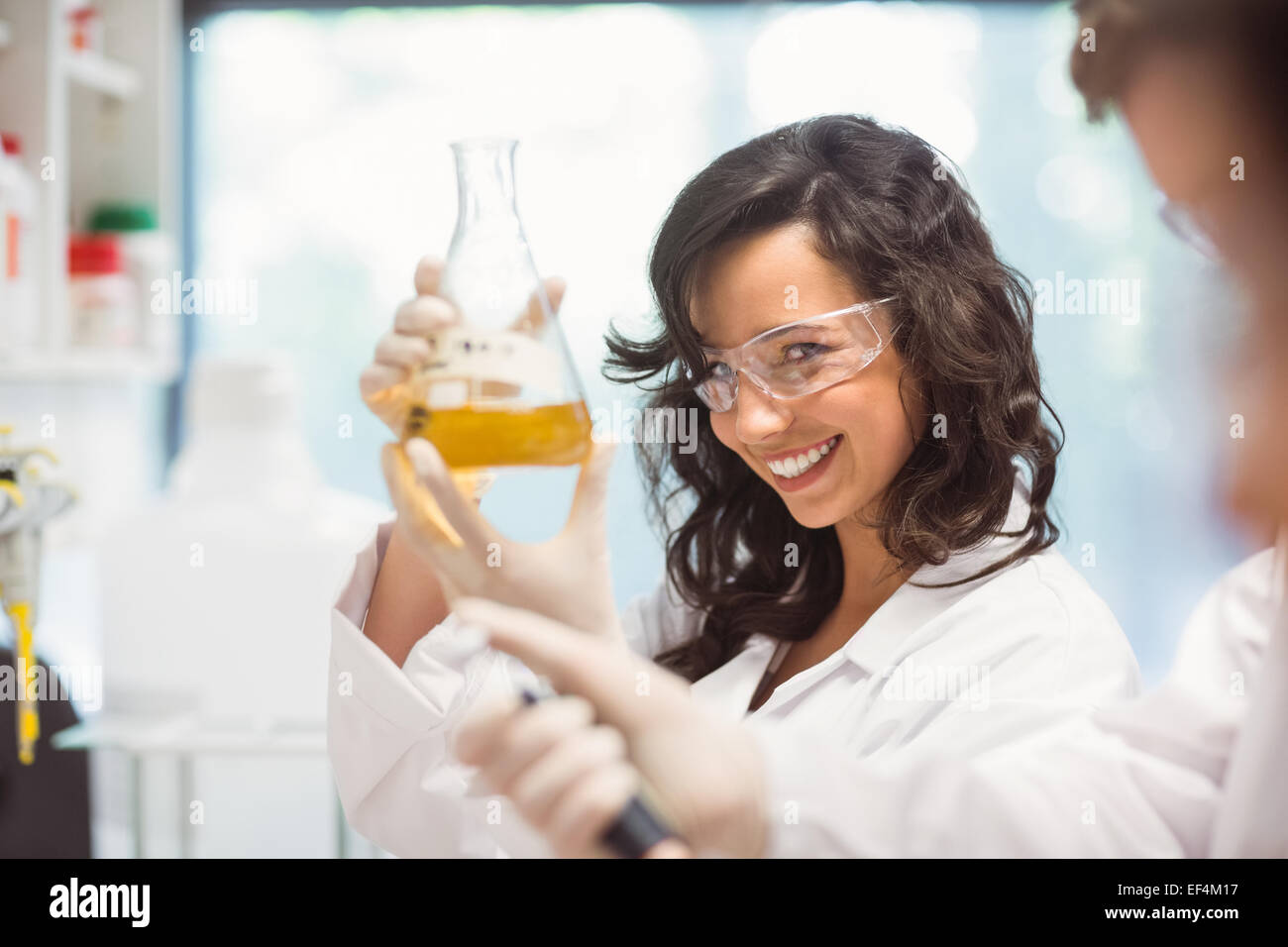 Pretty science student smiling and holding beaker Stock Photo - Alamy