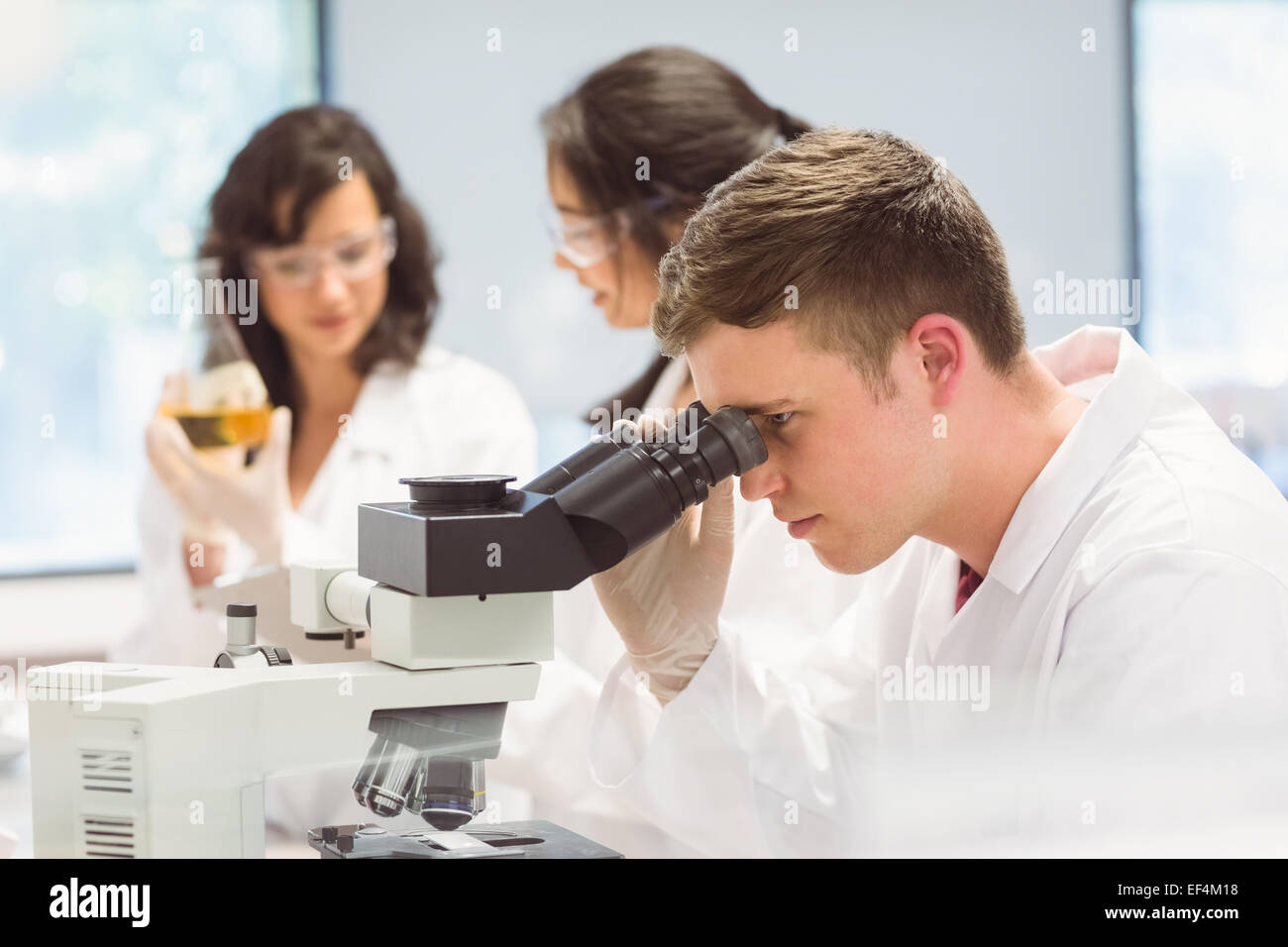 Science student looking through microscope in the lab Stock Photo - Alamy