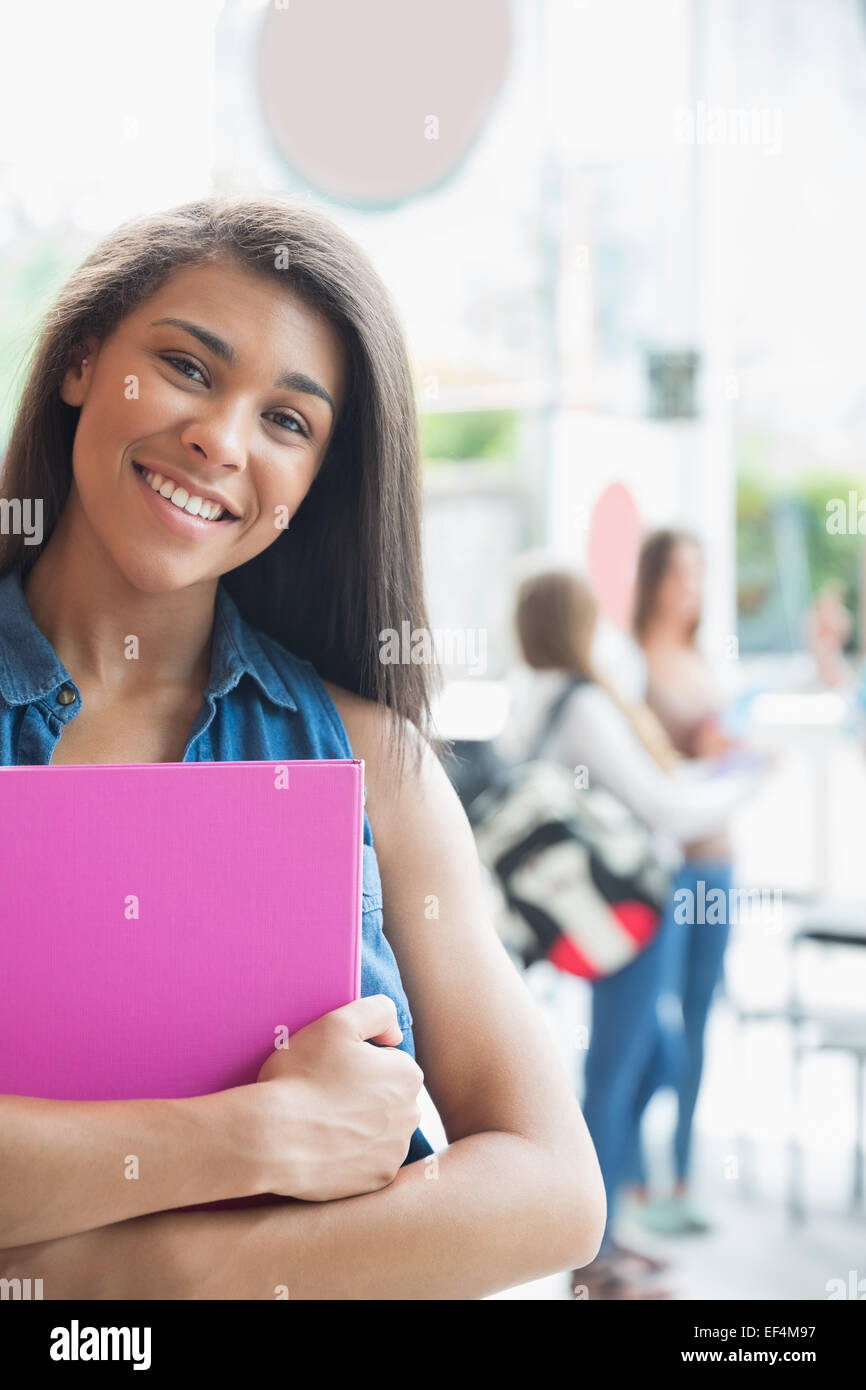 Pretty student smiling and holding notepads Stock Photo - Alamy