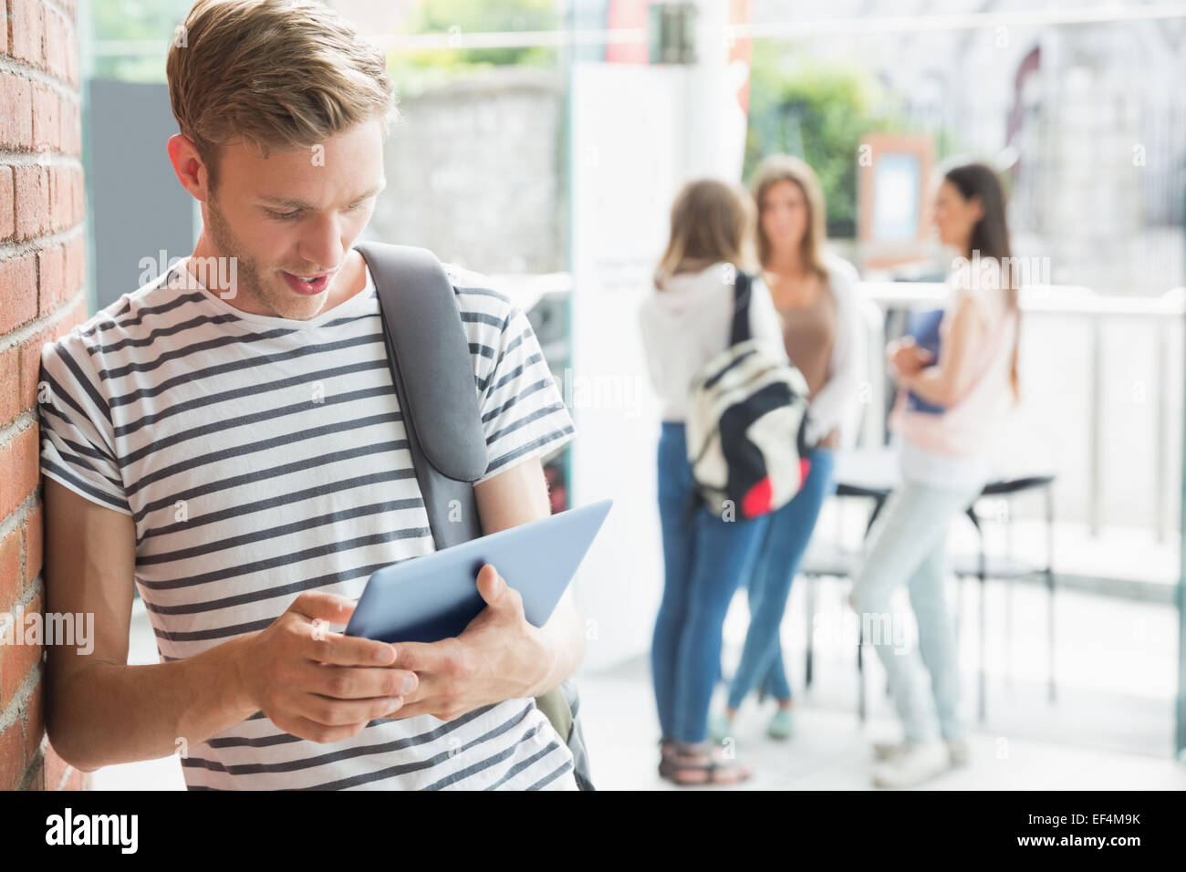 Handsome student smiling and holding tablet Stock Photo - Alamy