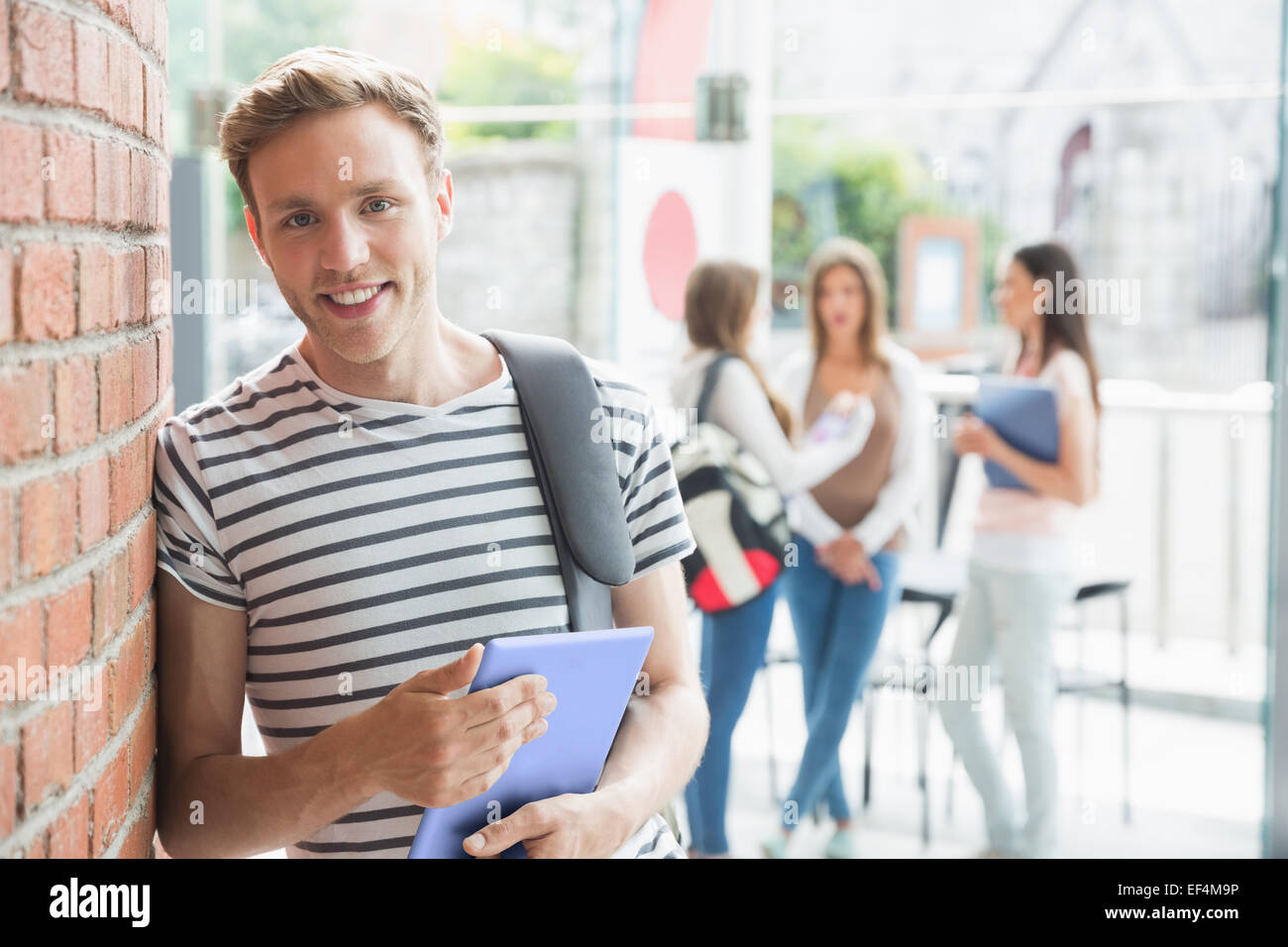 Handsome student smiling and holding tablet Stock Photo - Alamy
