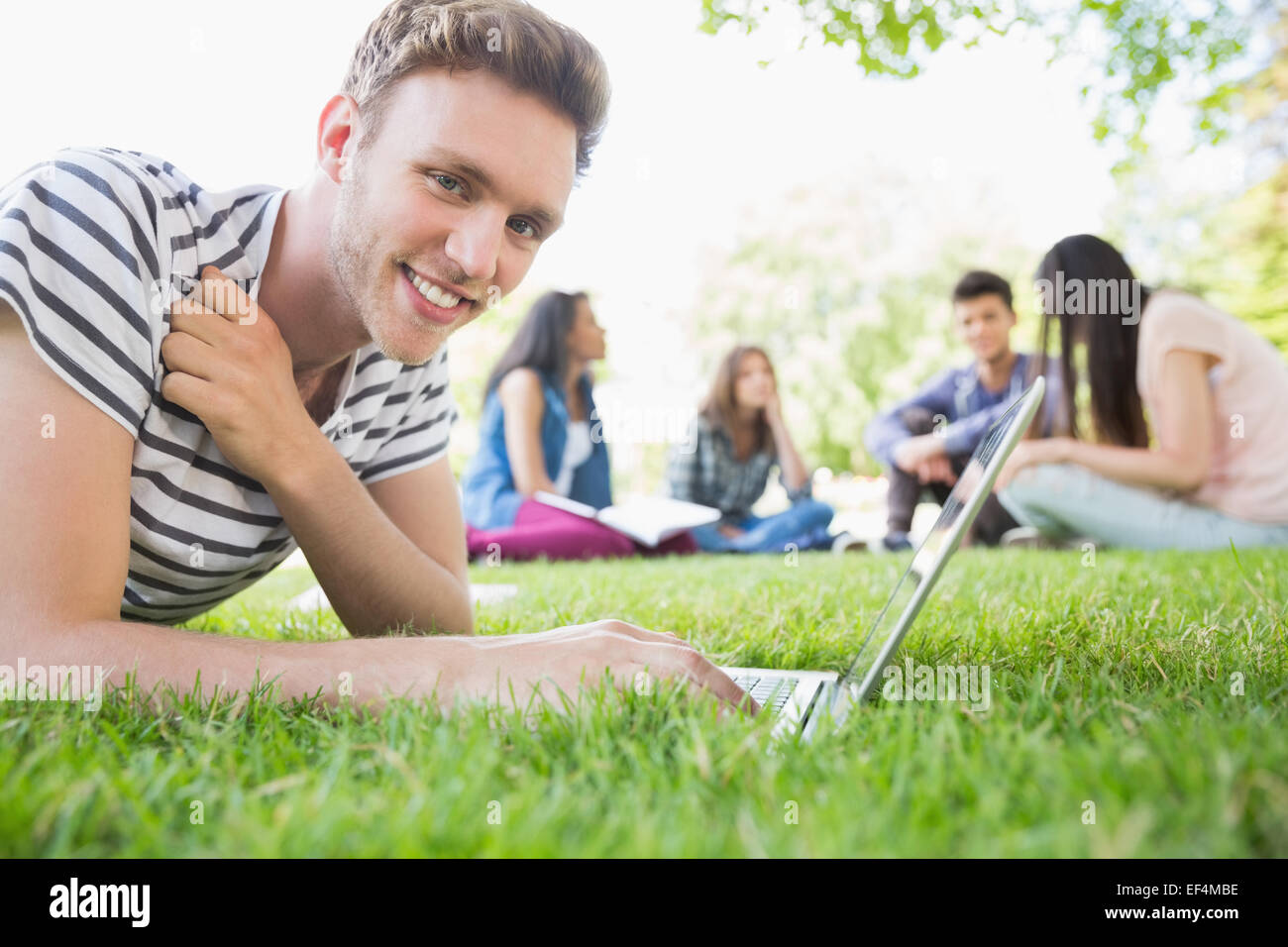 Happy student using his laptop outside Stock Photo - Alamy