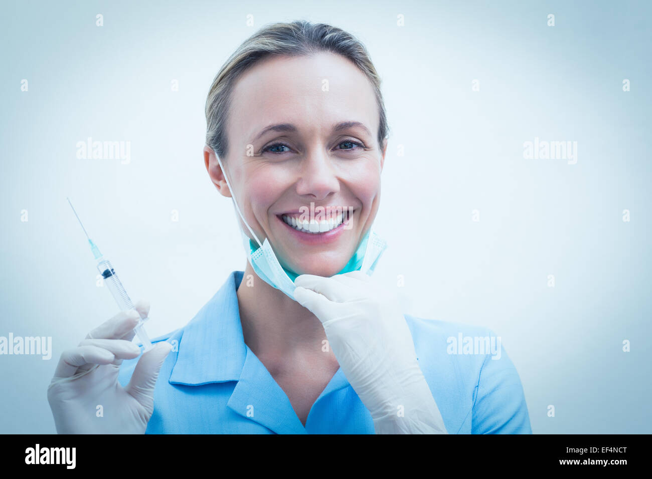 Smiling female dentist holding injection Stock Photo - Alamy