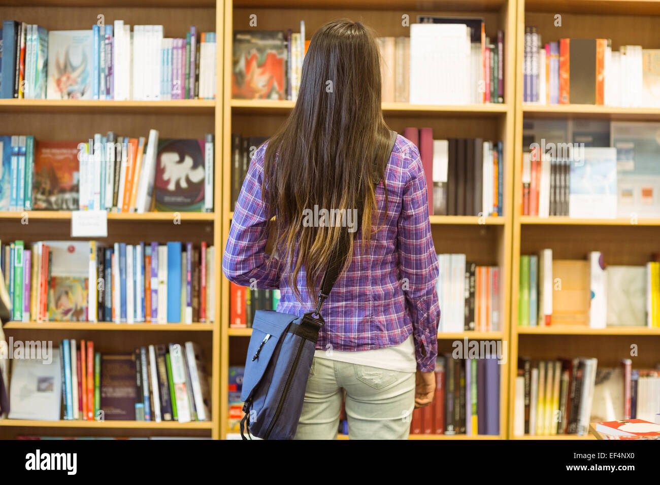 University student standing in the bookcase Stock Photo - Alamy