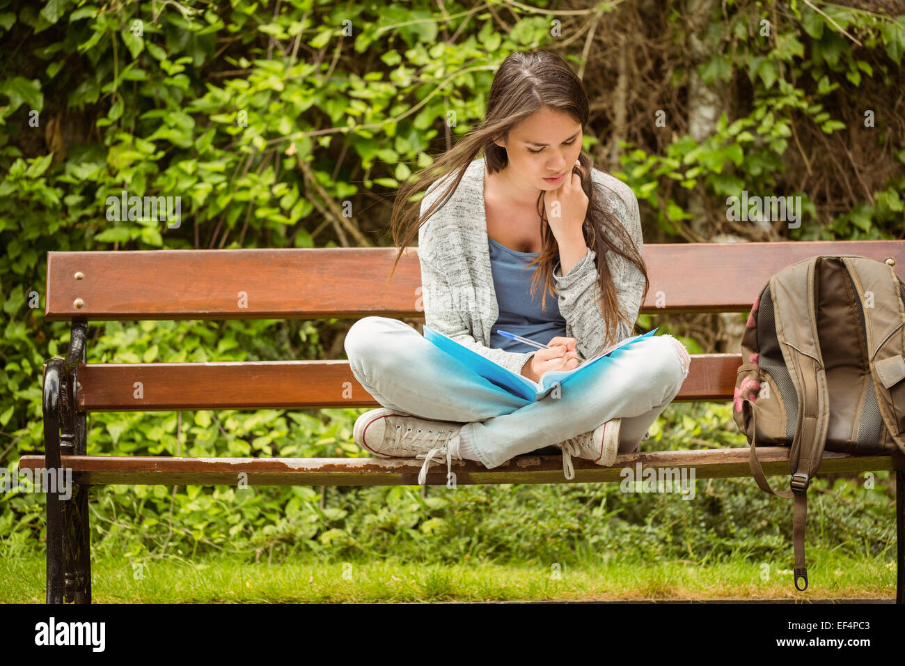 Smiling student sitting on bench reading book Stock Photo - Alamy