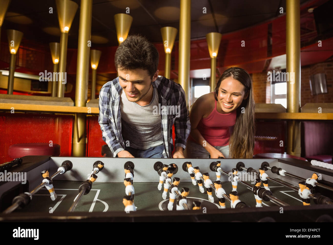 Smiling friends playing table football together Stock Photo - Alamy