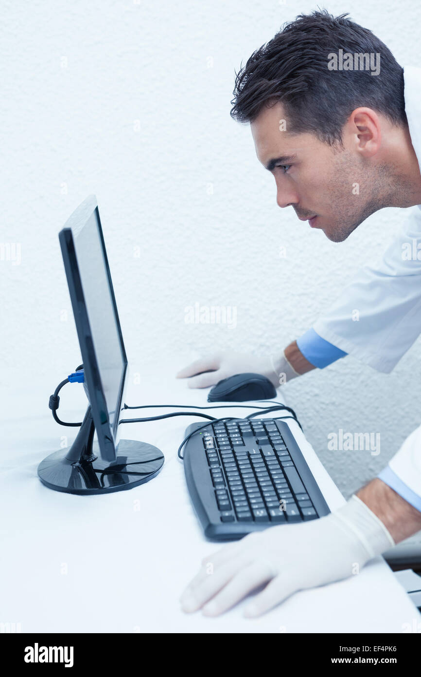 Concentrated male dentist looking at computer monitor Stock Photo - Alamy
