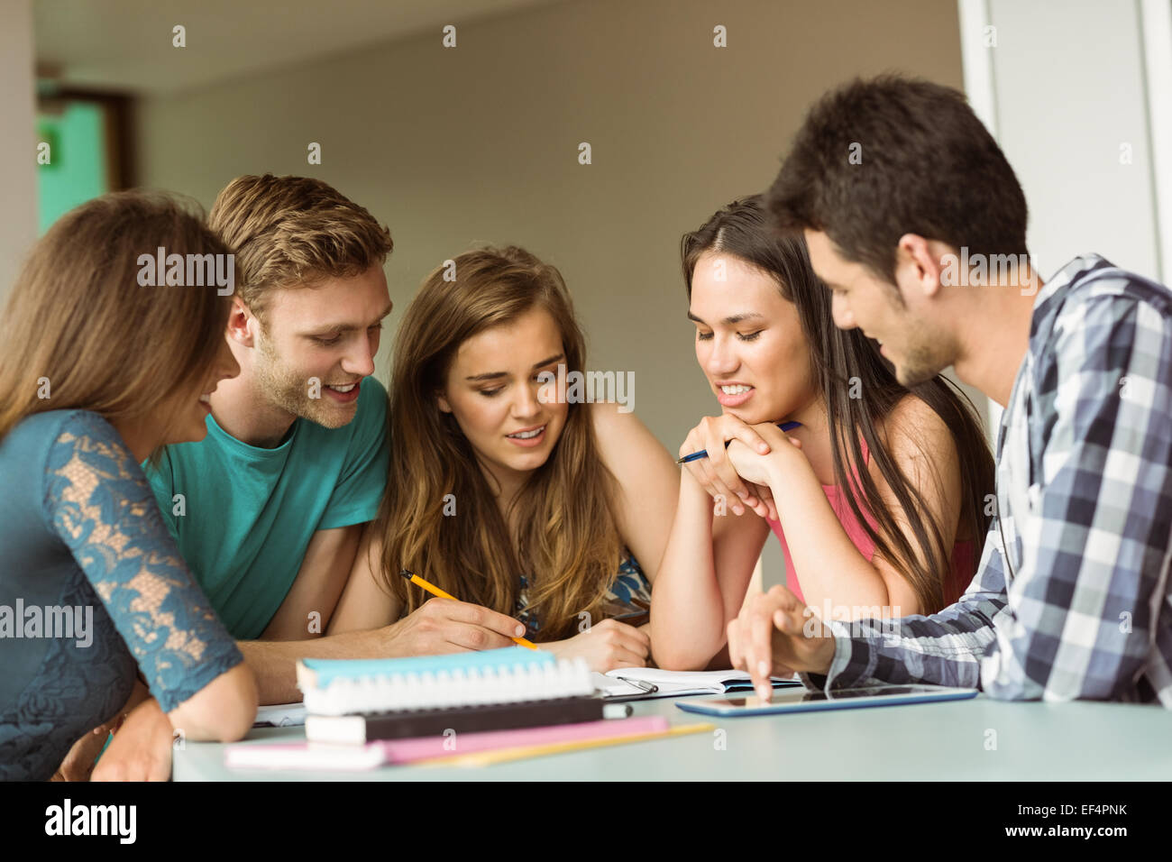 Smiling friends sitting studying together Stock Photo - Alamy