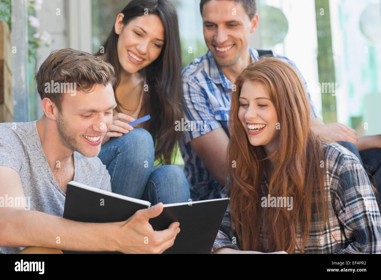 Happy students looking at book outside on campus Stock Photo - Alamy