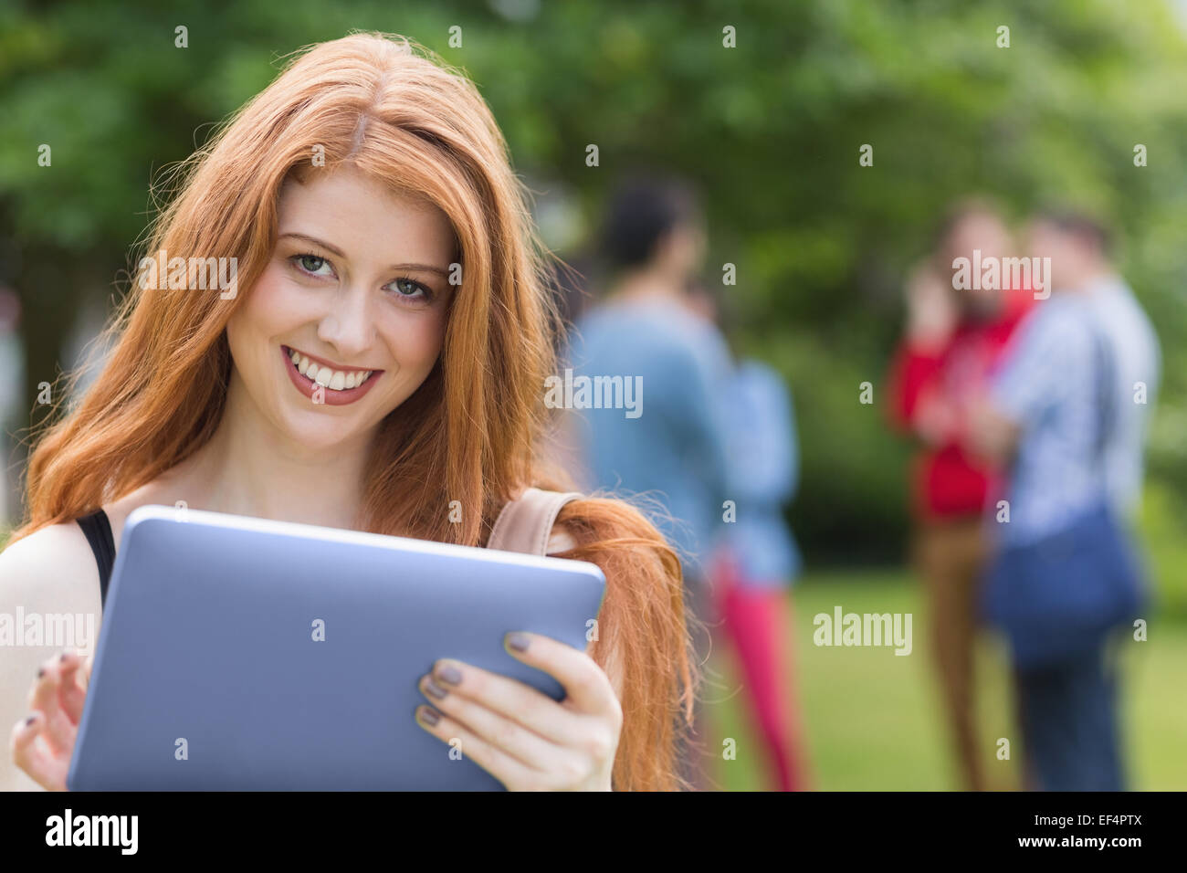 Pretty student smiling at camera using tablet pc Stock Photo - Alamy