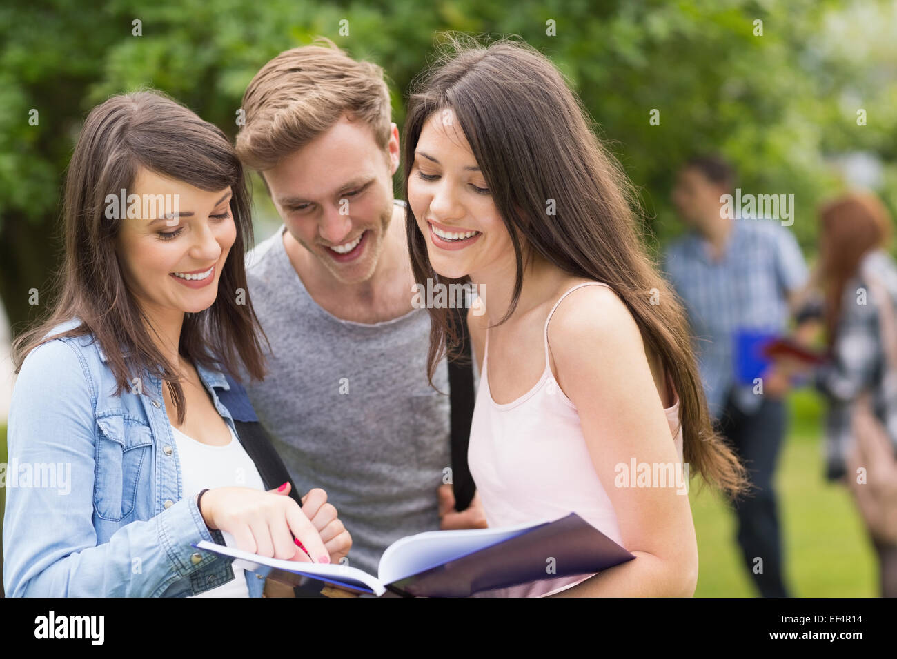 Happy students reading from notepad Stock Photo - Alamy