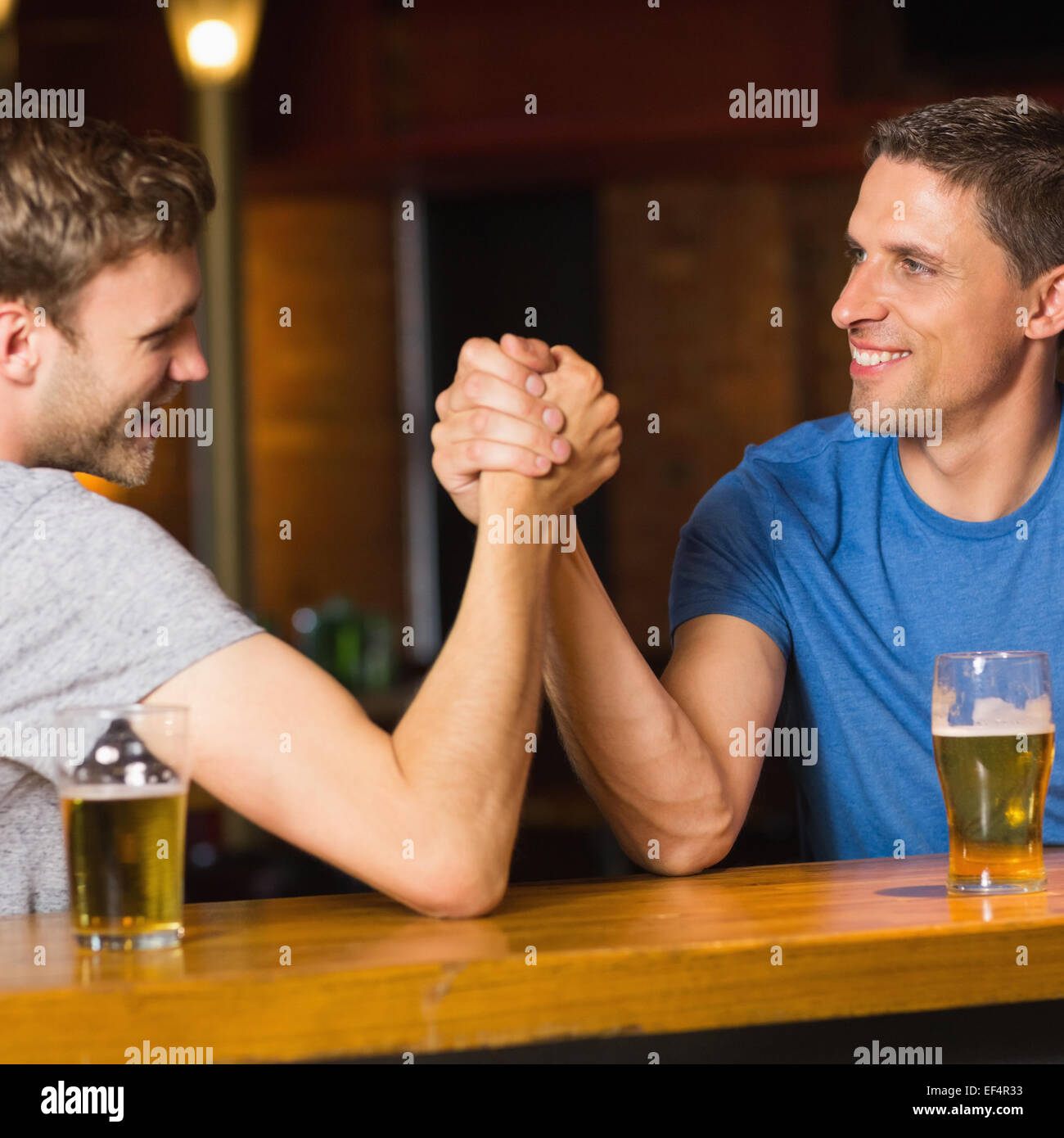 Happy friend arm wrestling each other Stock Photo - Alamy