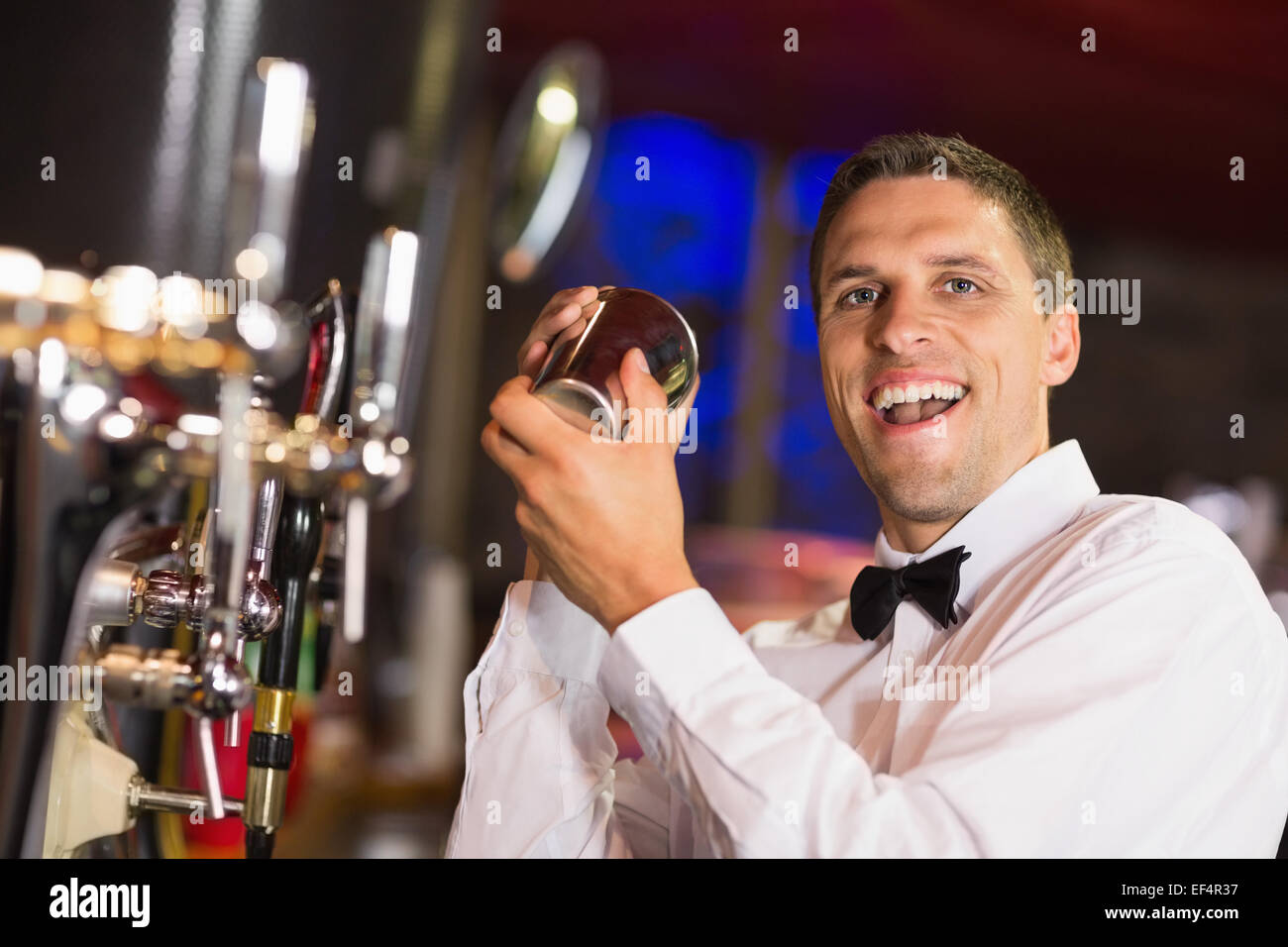 Handsome barman smiling at camera making a cocktail Stock Photo - Alamy