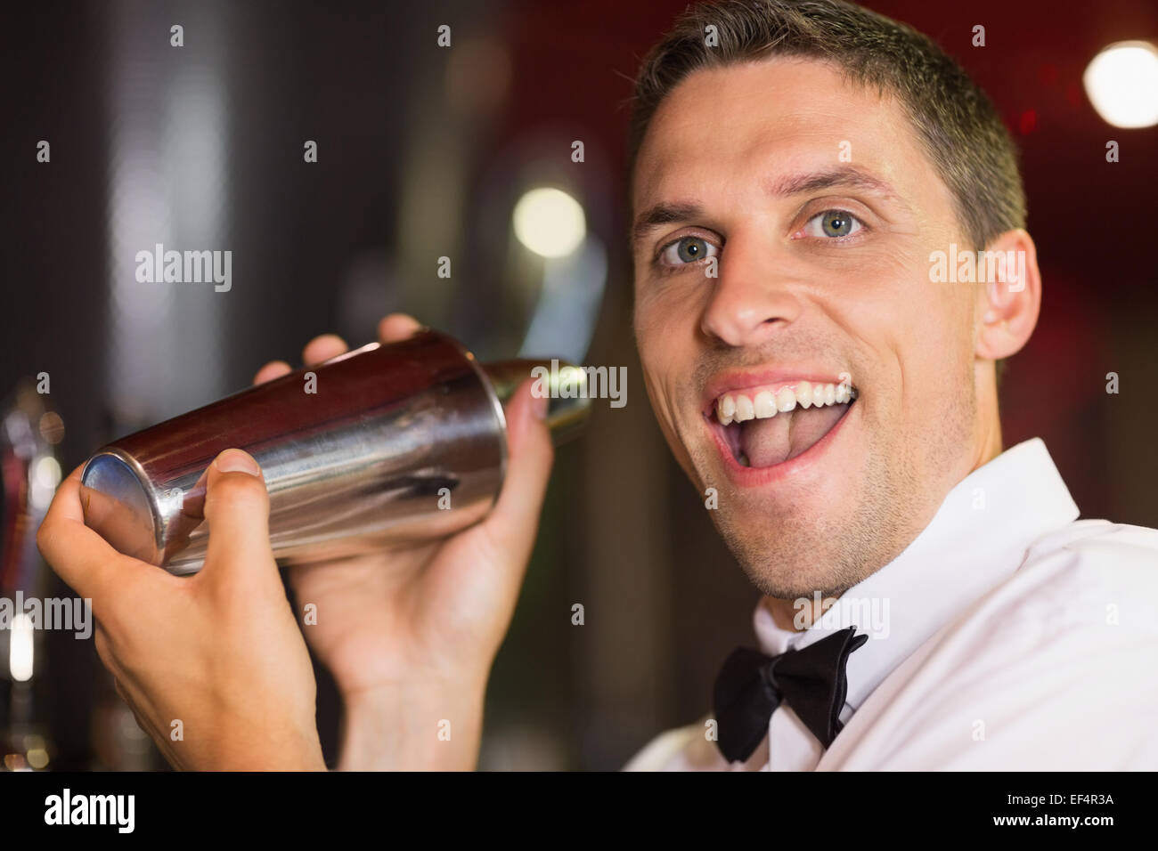 Handsome barman smiling at camera making a cocktail Stock Photo - Alamy