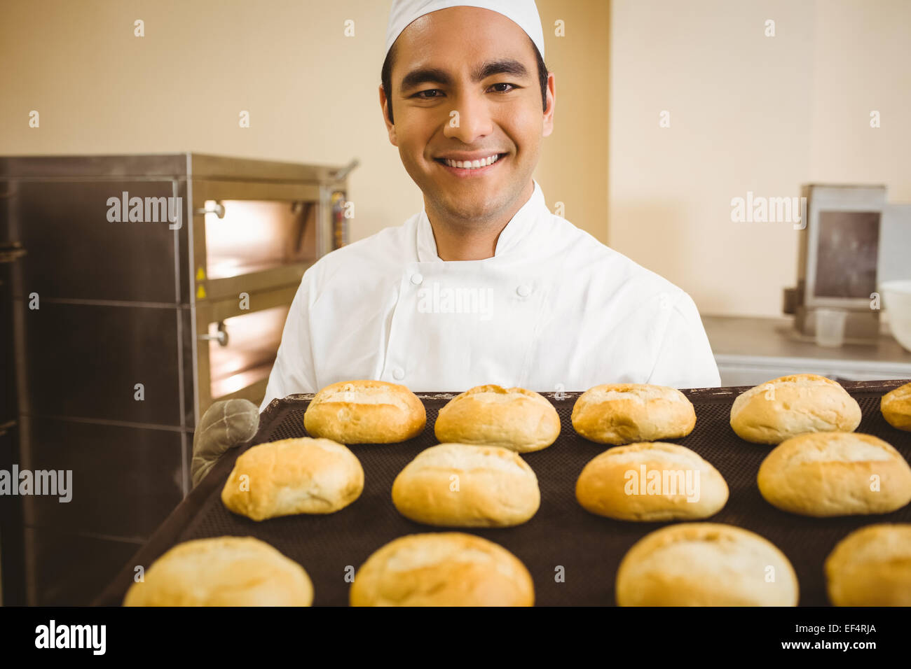 Baker smiling at camera holding tray of rolls Stock Photo - Alamy