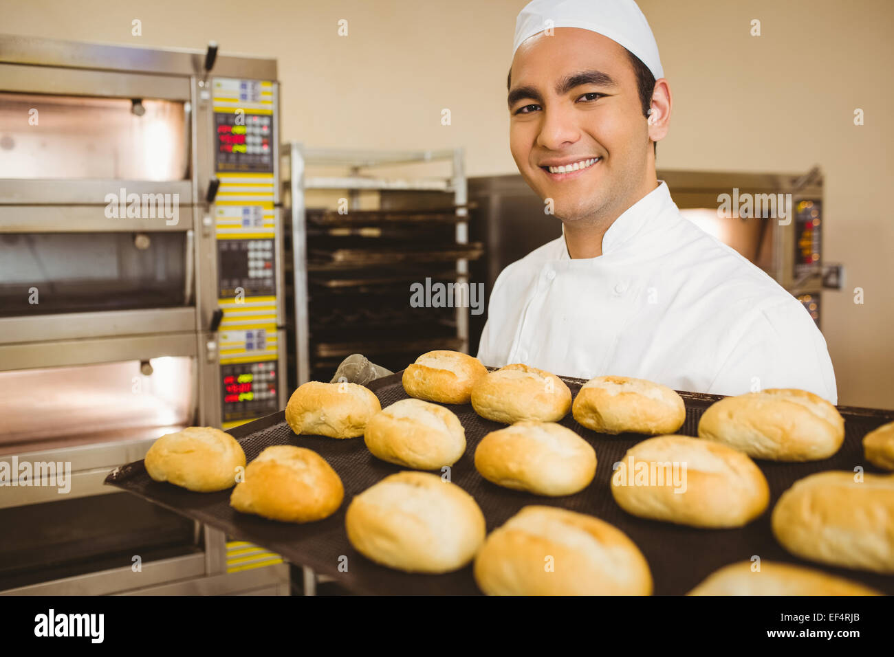 Baker smiling at camera holding tray of rolls Stock Photo - Alamy