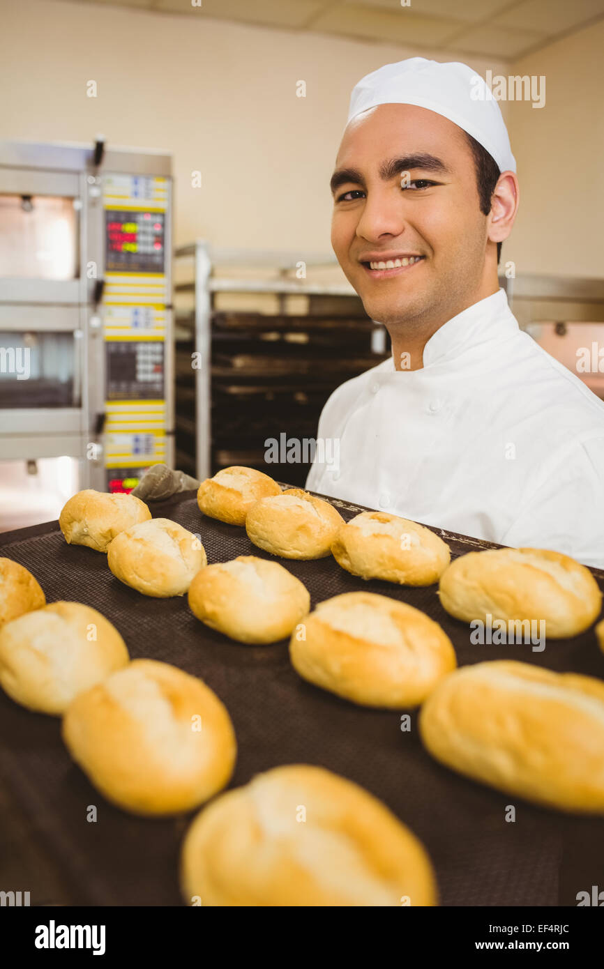 Baker smiling at camera holding tray of rolls Stock Photo - Alamy