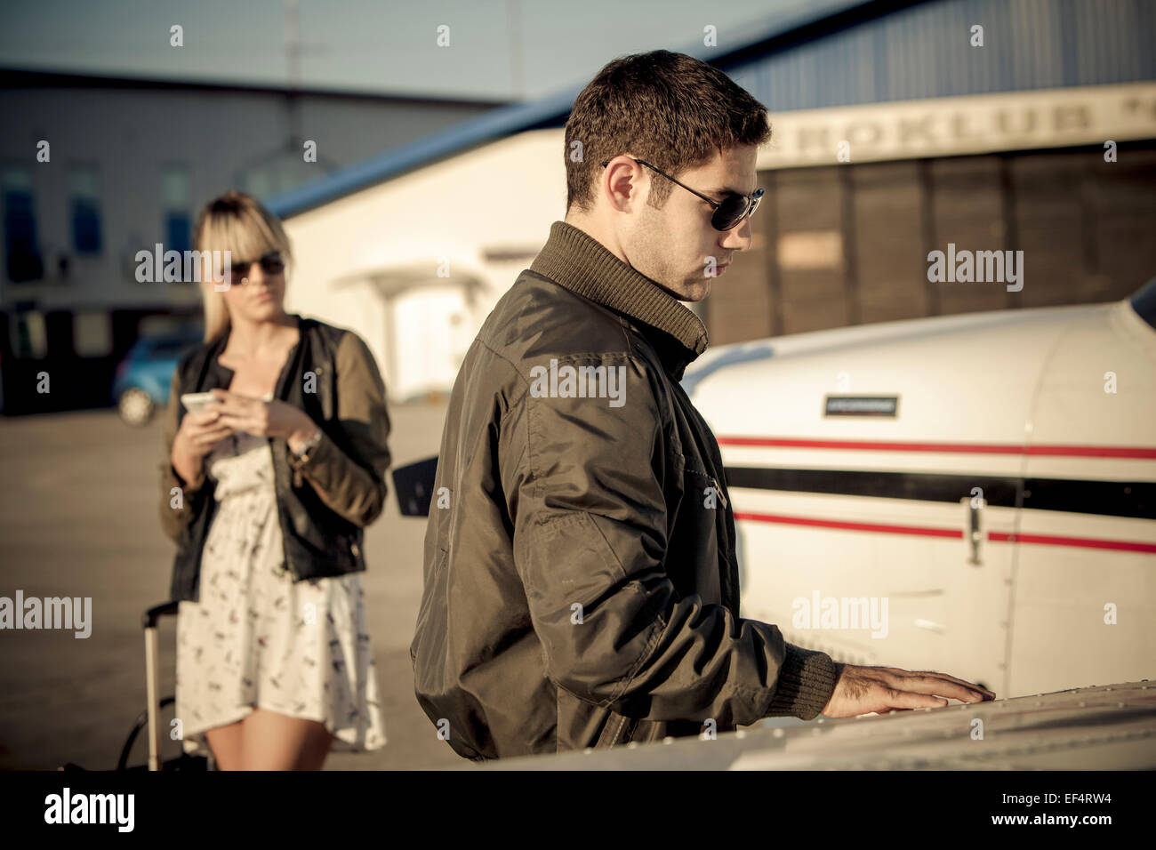 Pilot checking wing of propeller airplane, woman is watching Stock ...