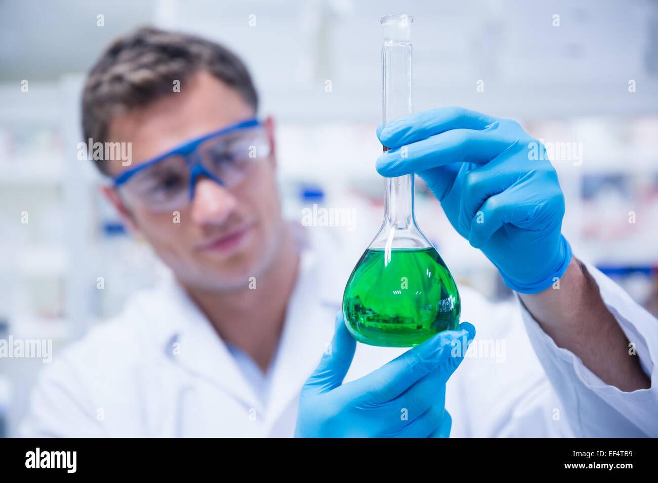 Chemist holding up beaker of green chemical Stock Photo - Alamy
