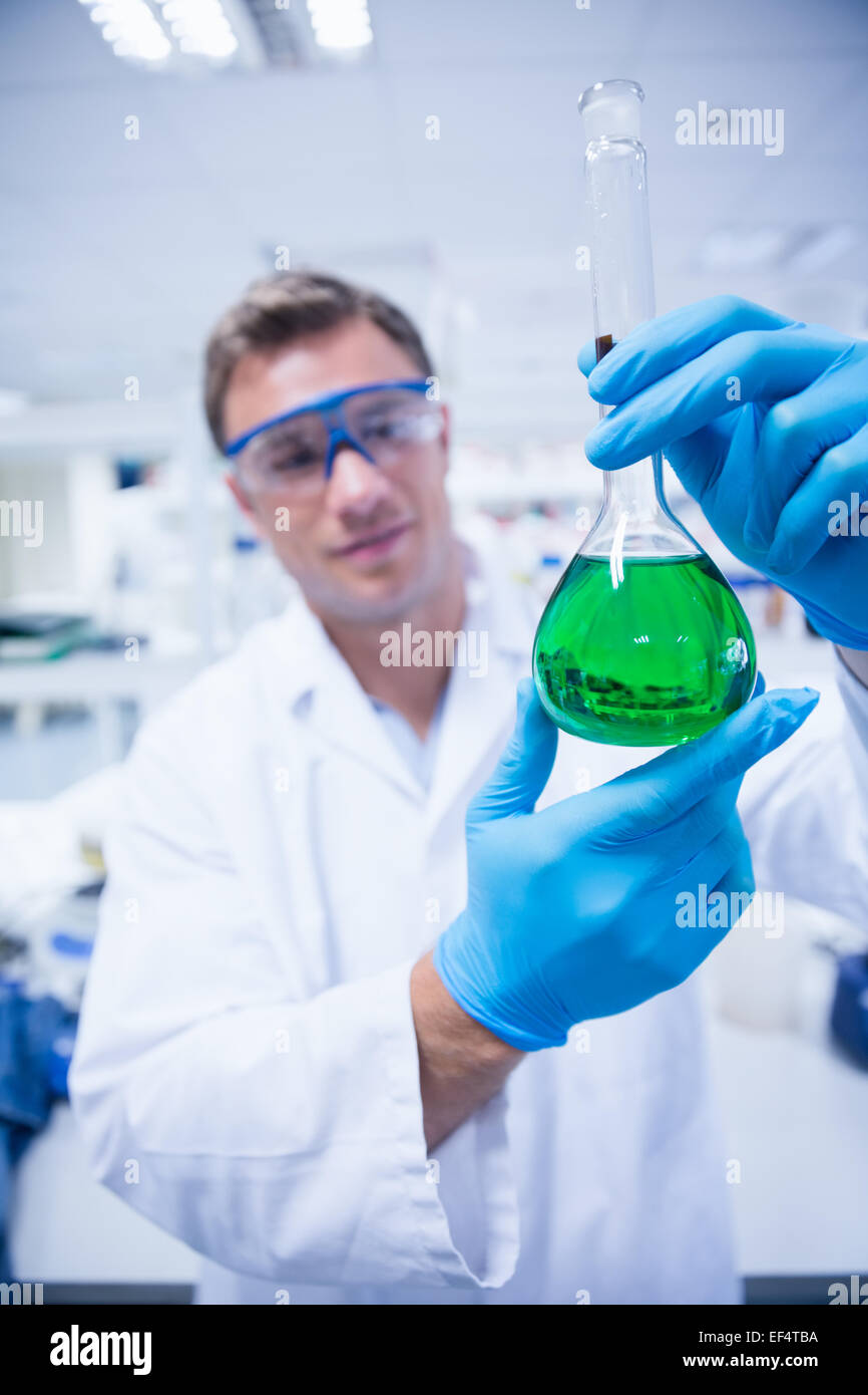 Chemist holding up beaker of green chemical Stock Photo - Alamy