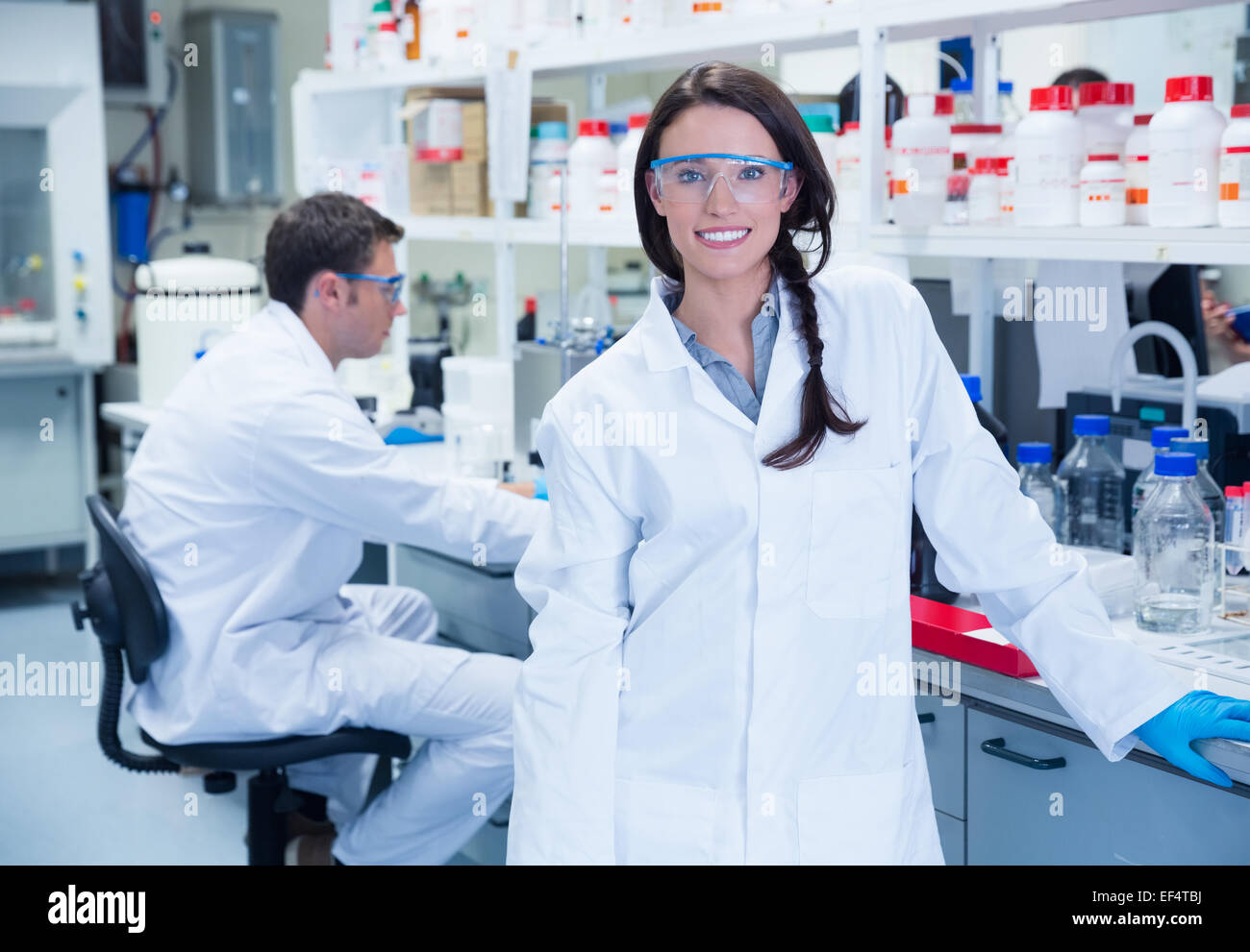 Portrait of a smiling chemist leaning against desk Stock Photo - Alamy