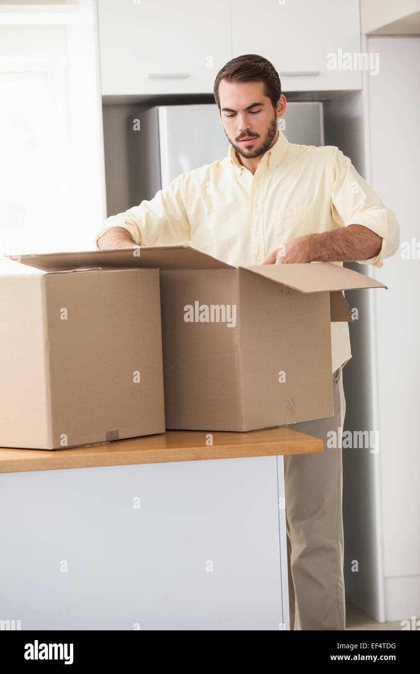 Young man unpacking boxes in kitchen Stock Photo - Alamy
