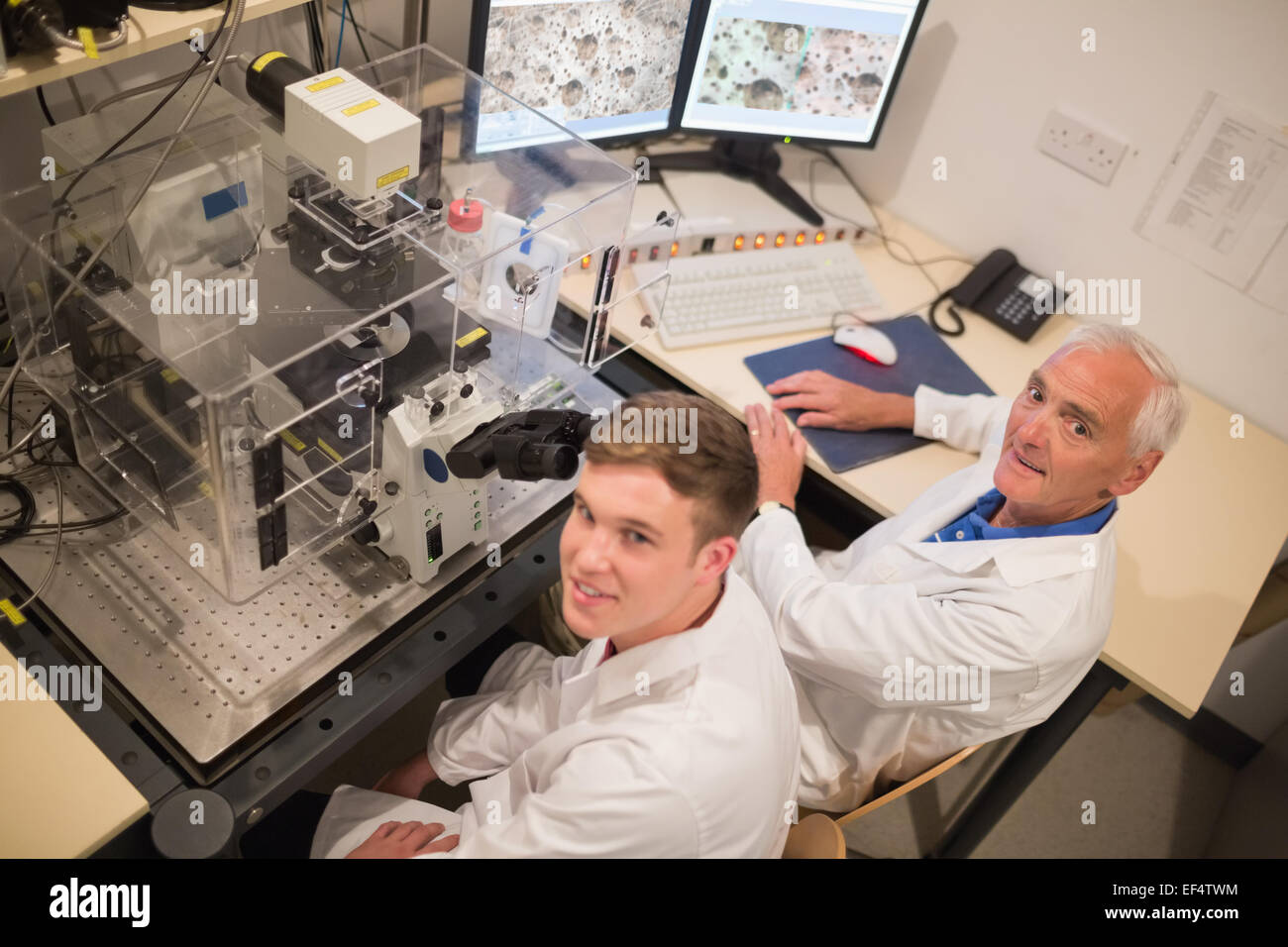 Biochemist and student looking at microscopic images on computer Stock ...