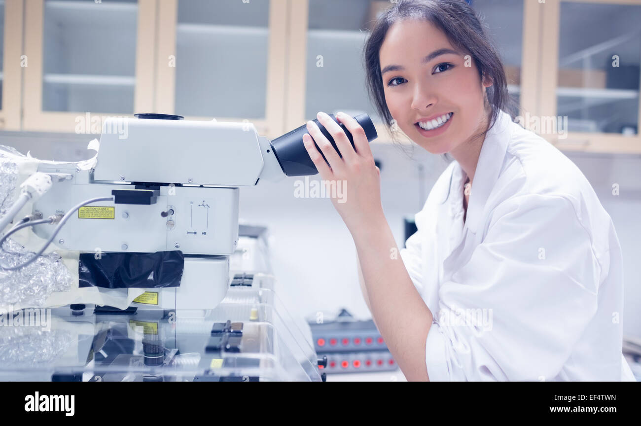Pretty scientist smiling at the camera using microscope Stock Photo - Alamy