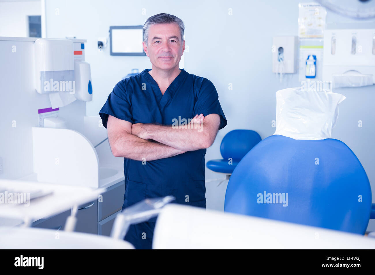 Dentist in blue scrubs smiling at camera Stock Photo - Alamy
