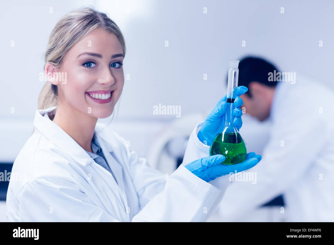 Science student holding green chemical in beaker Stock Photo - Alamy