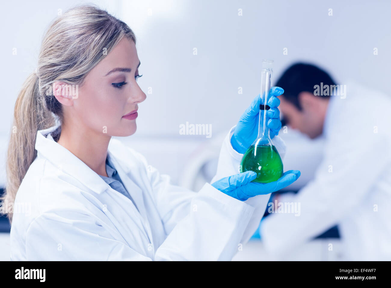 Science student holding green chemical in beaker Stock Photo - Alamy