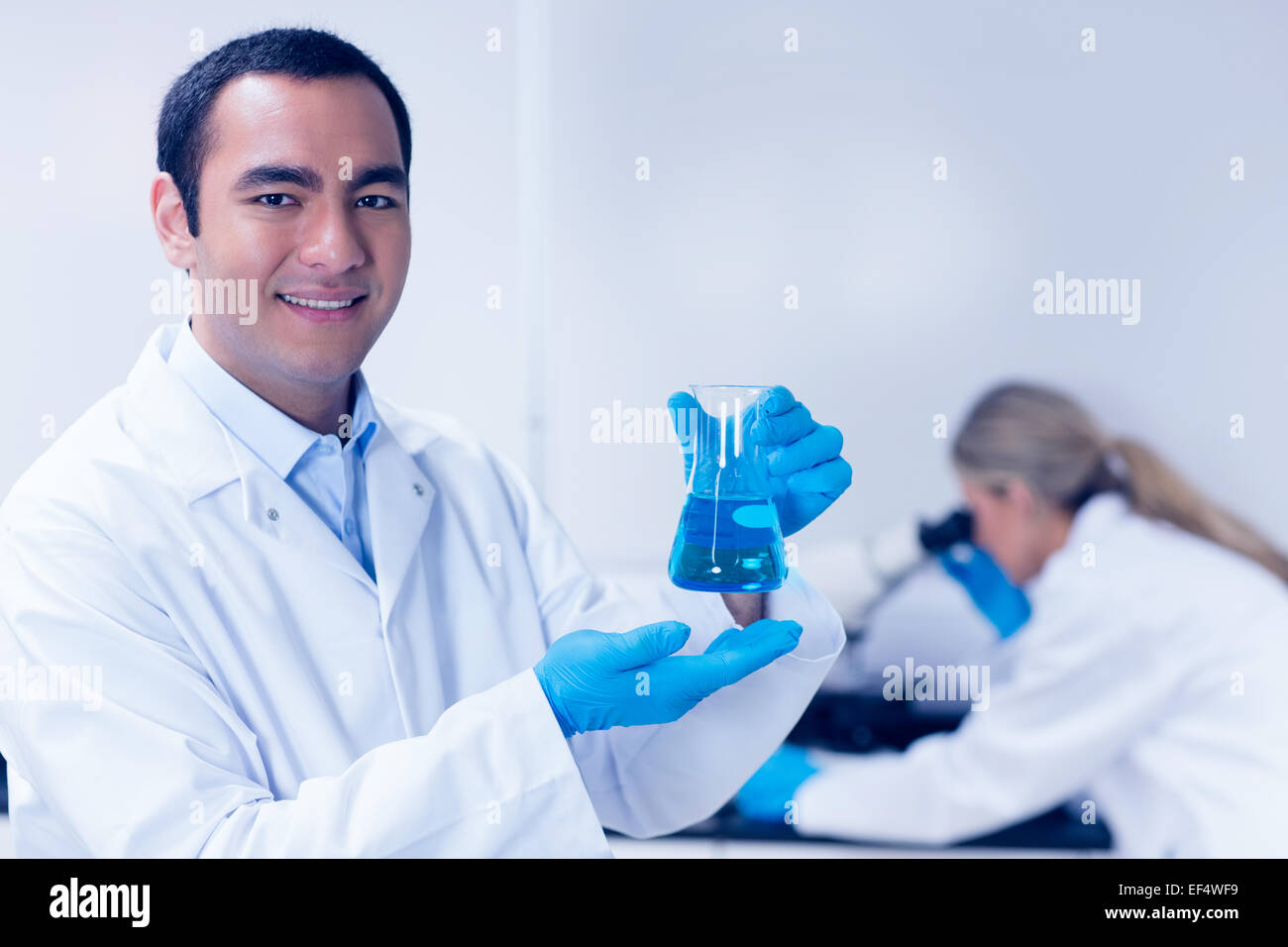 Science student holding blue chemical in beaker Stock Photo - Alamy