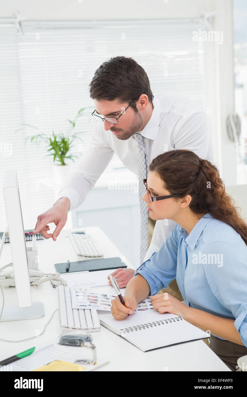 Focused colleagues using computer together Stock Photo - Alamy