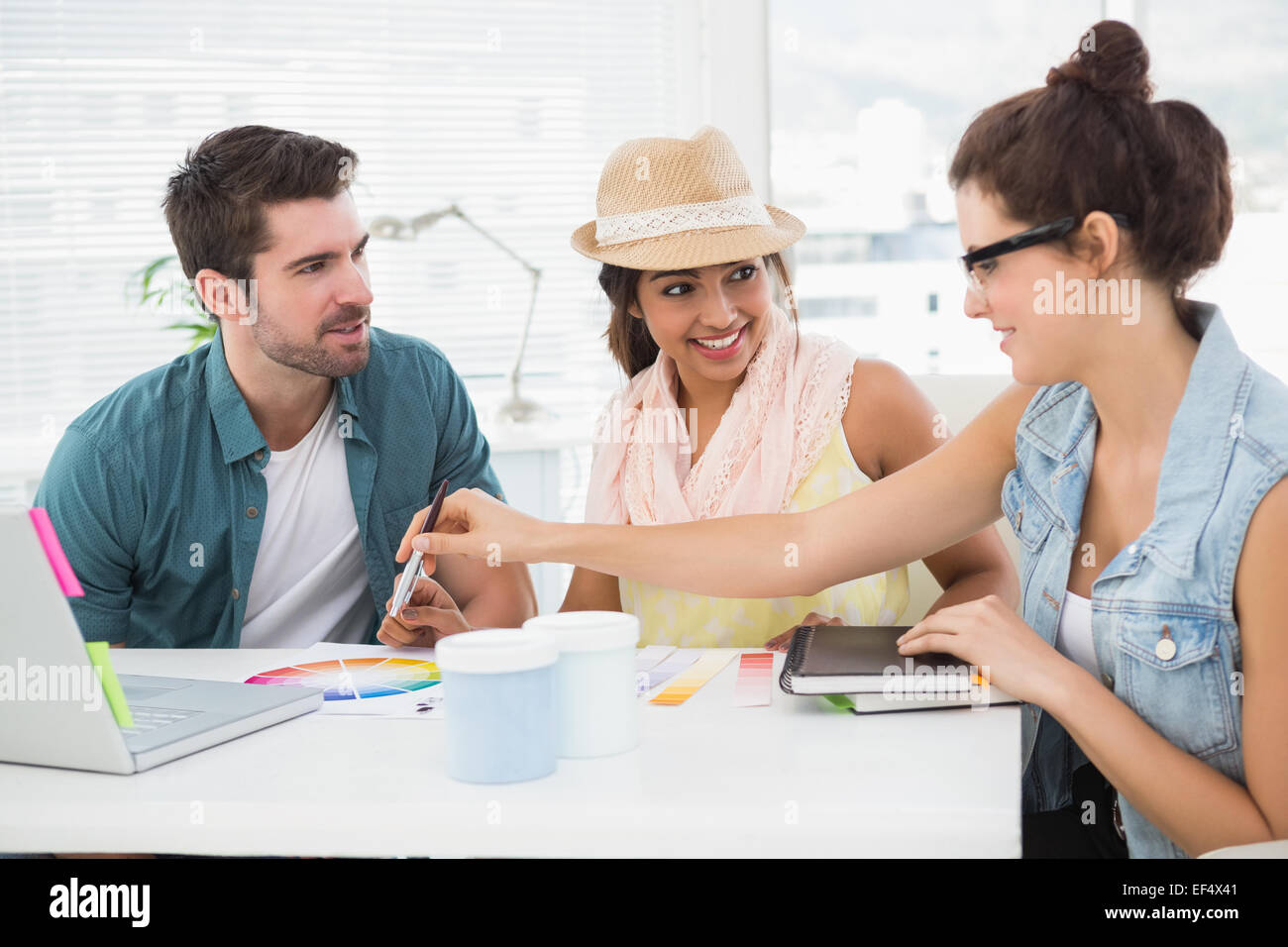 Smiling colleagues speaking together at desk Stock Photo - Alamy