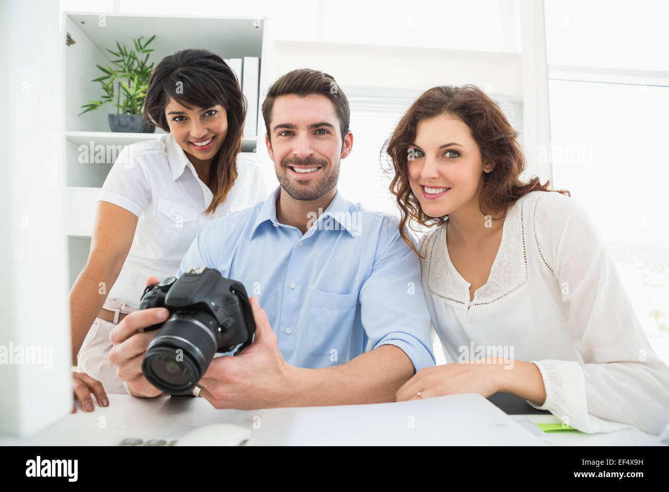 Happy teamwork posing with digital camera Stock Photo - Alamy